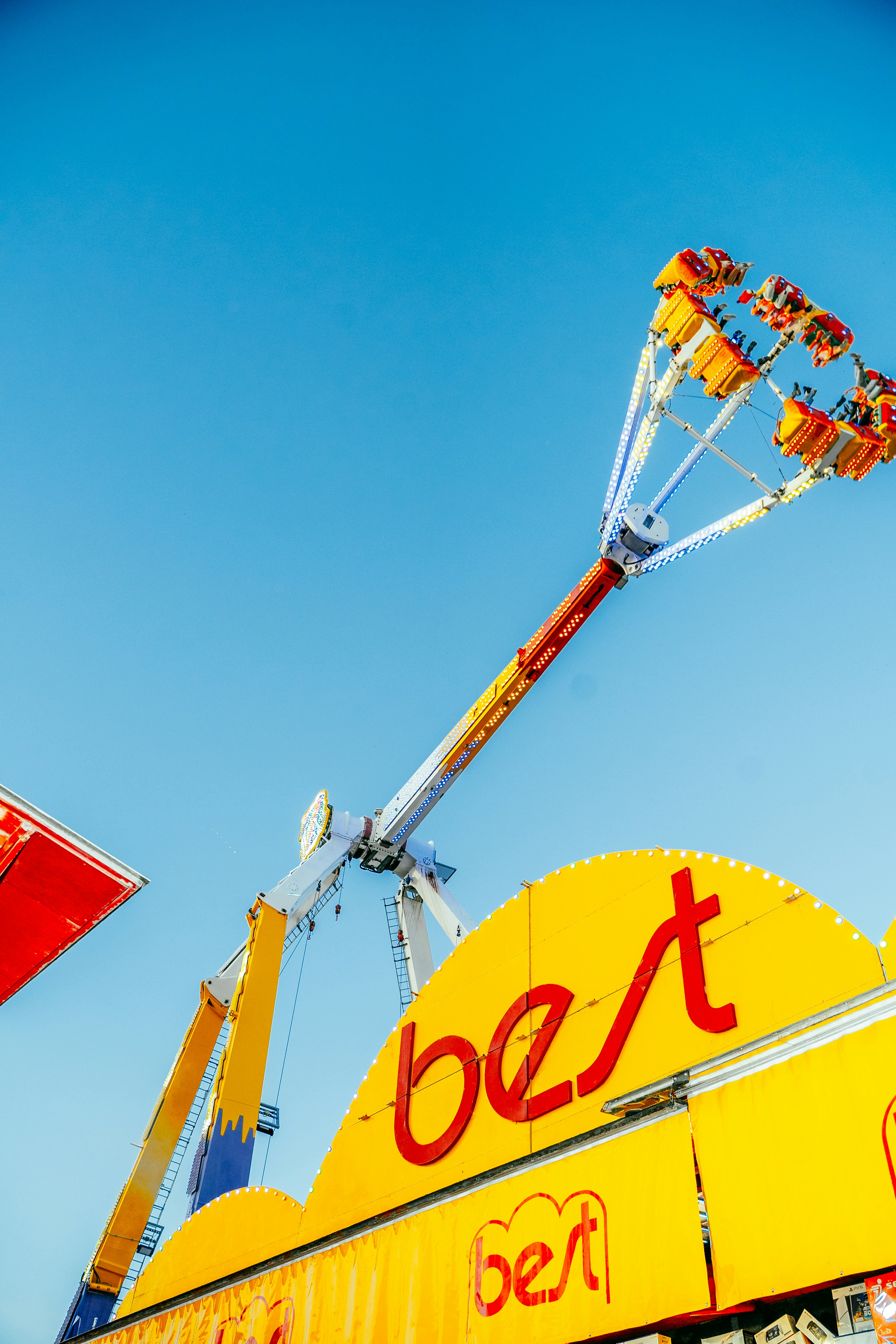 Sunlit Thrill: The Flying Carousels Above a Bright Carnival Facade