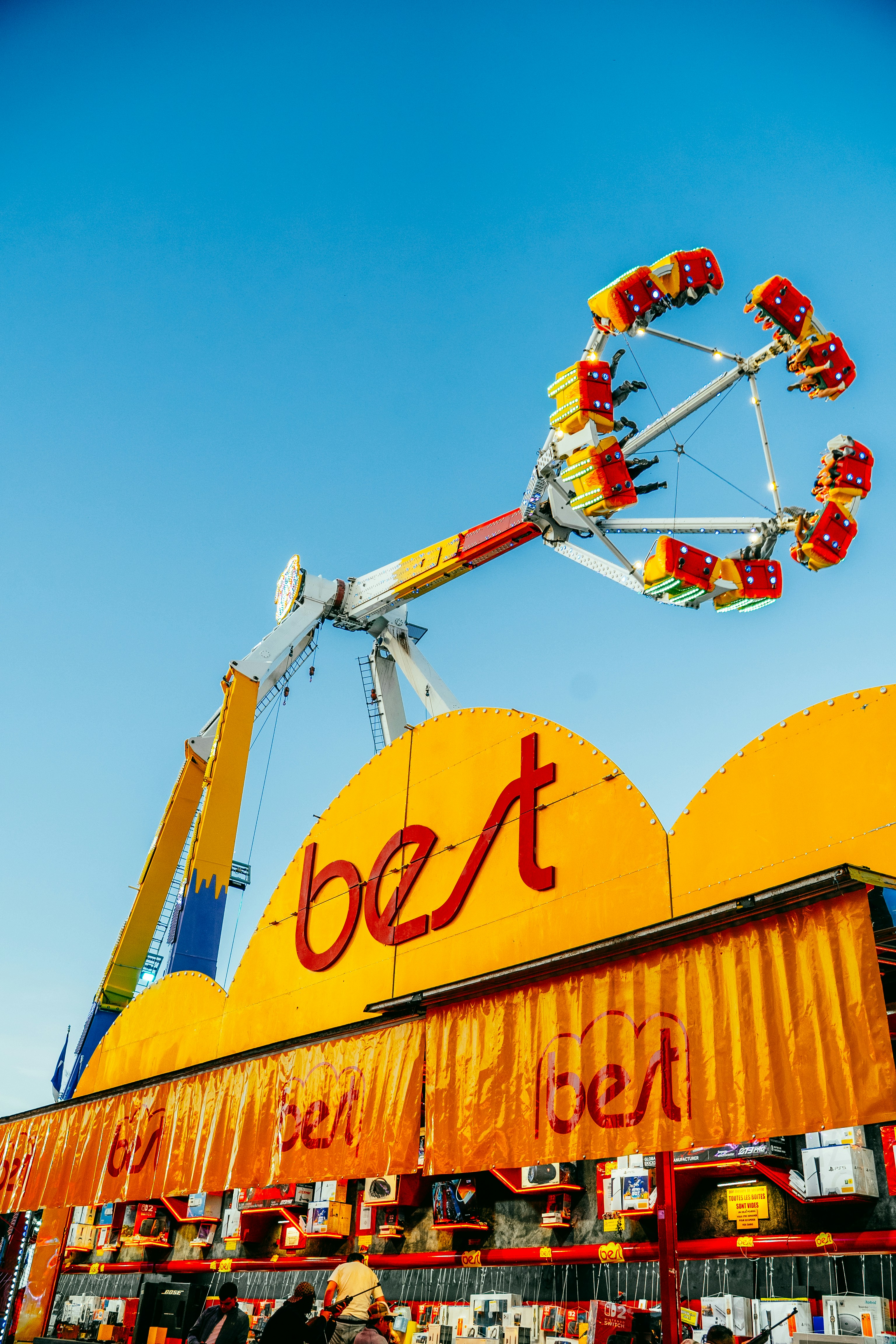Yellow Arcade Aerial: A Carnival Ride Soars against a Clear Blue Sky