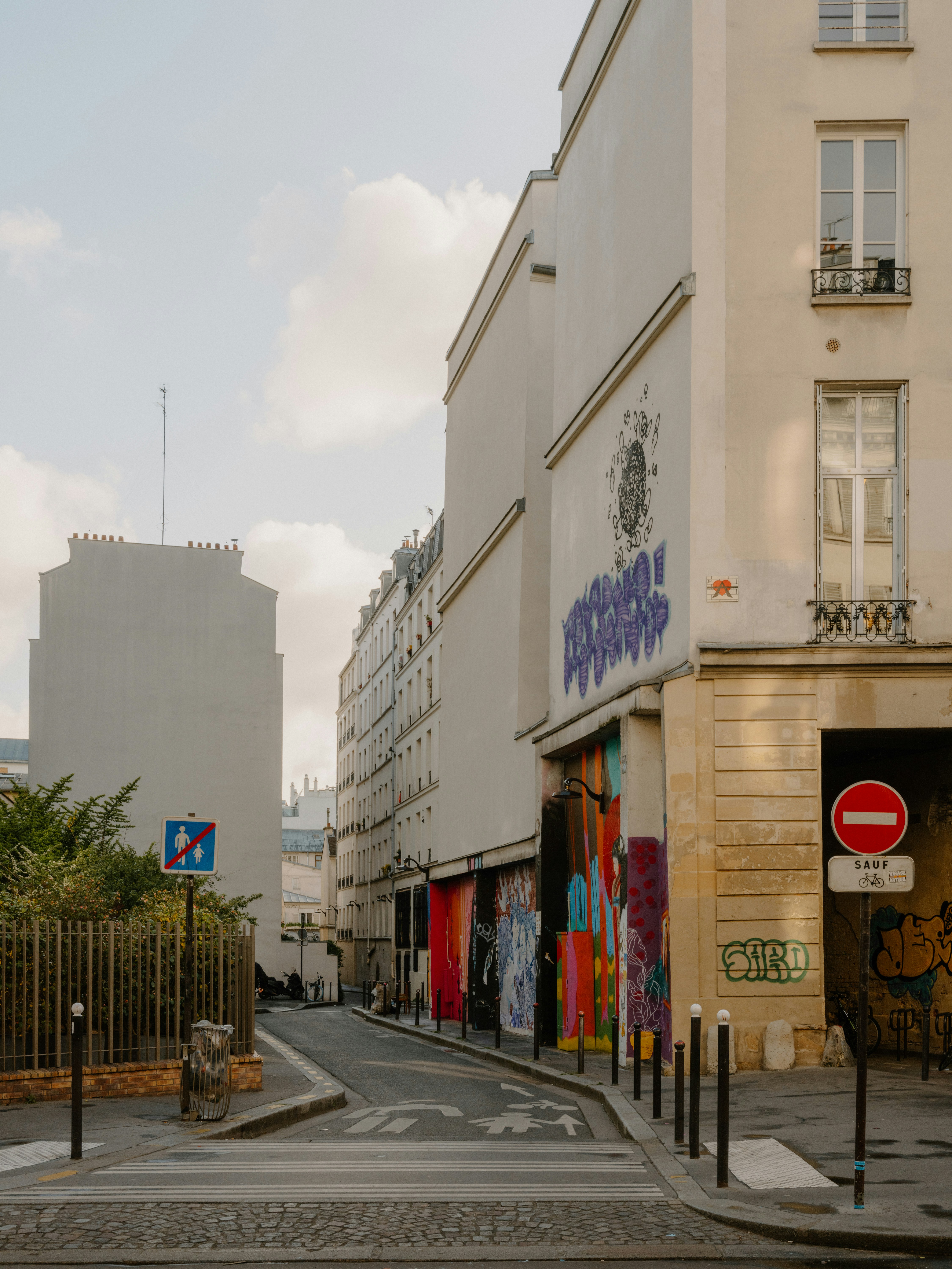 Sunlit Parisian Street Corridor with Graffiti Facades