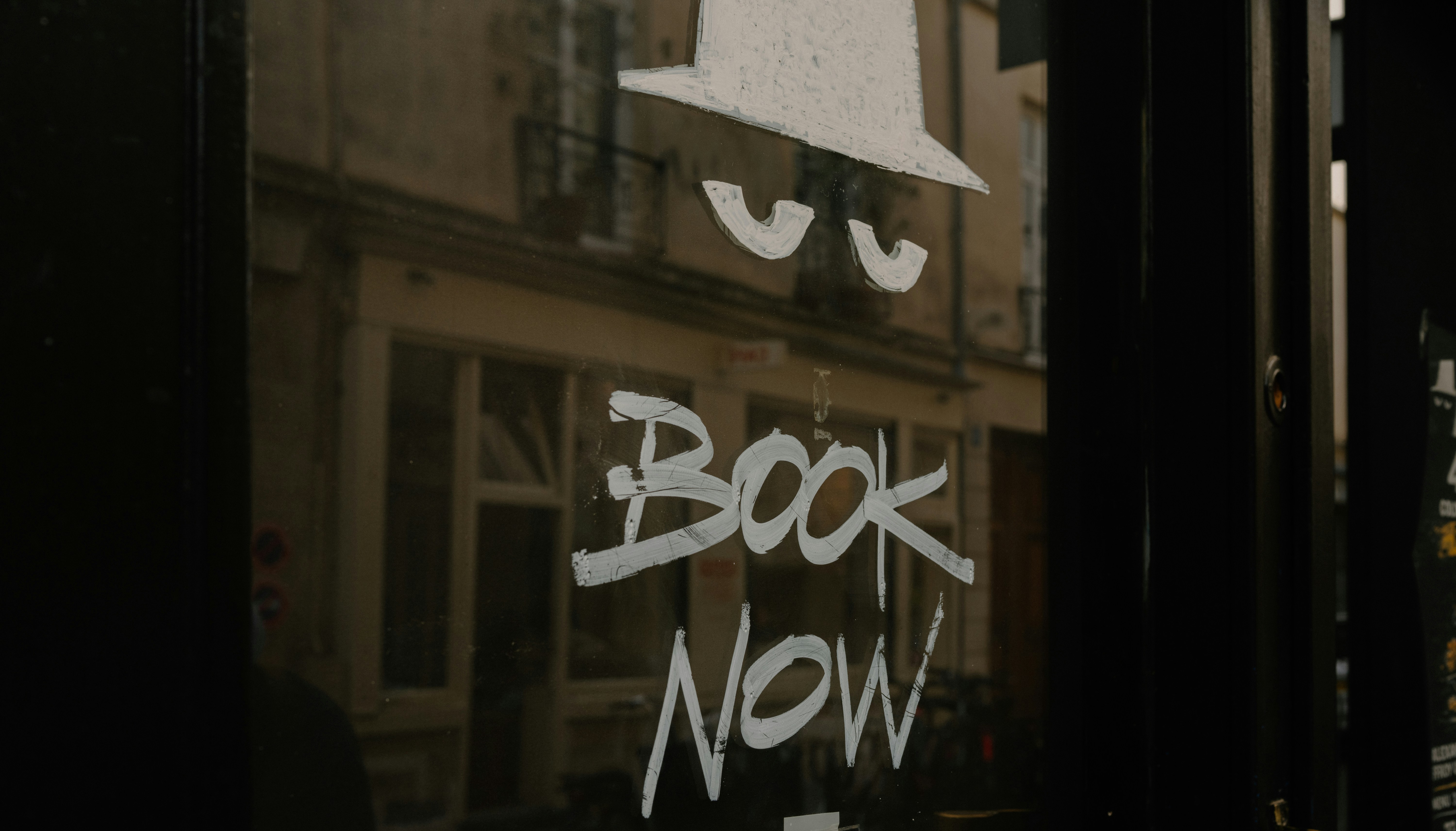 Bookstore Window Graffiti: 'Book Now' Reflected in Quiet Street
