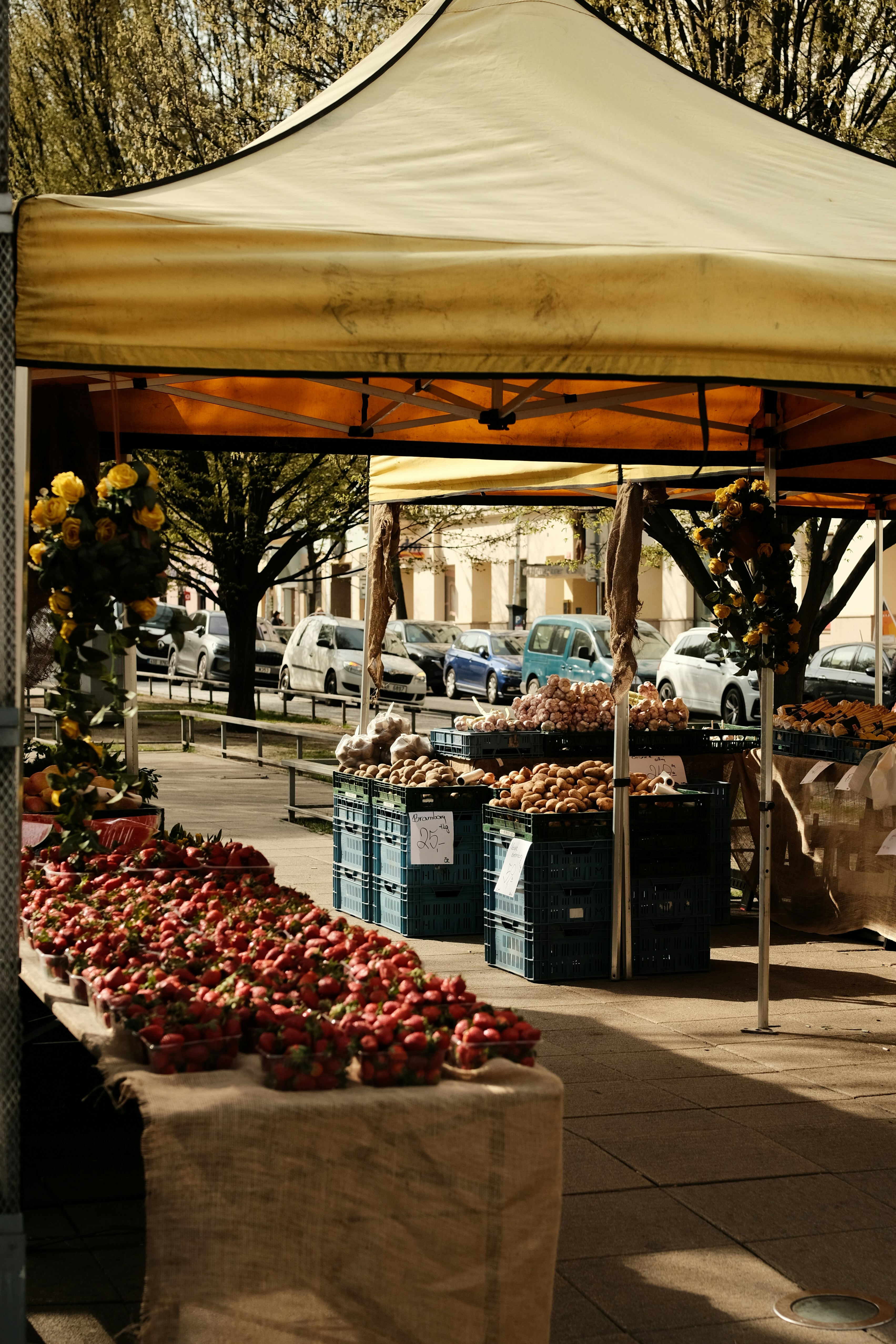 Market Stall Under a Golden Canopy: Produce, Cars, and Soft Sunlight