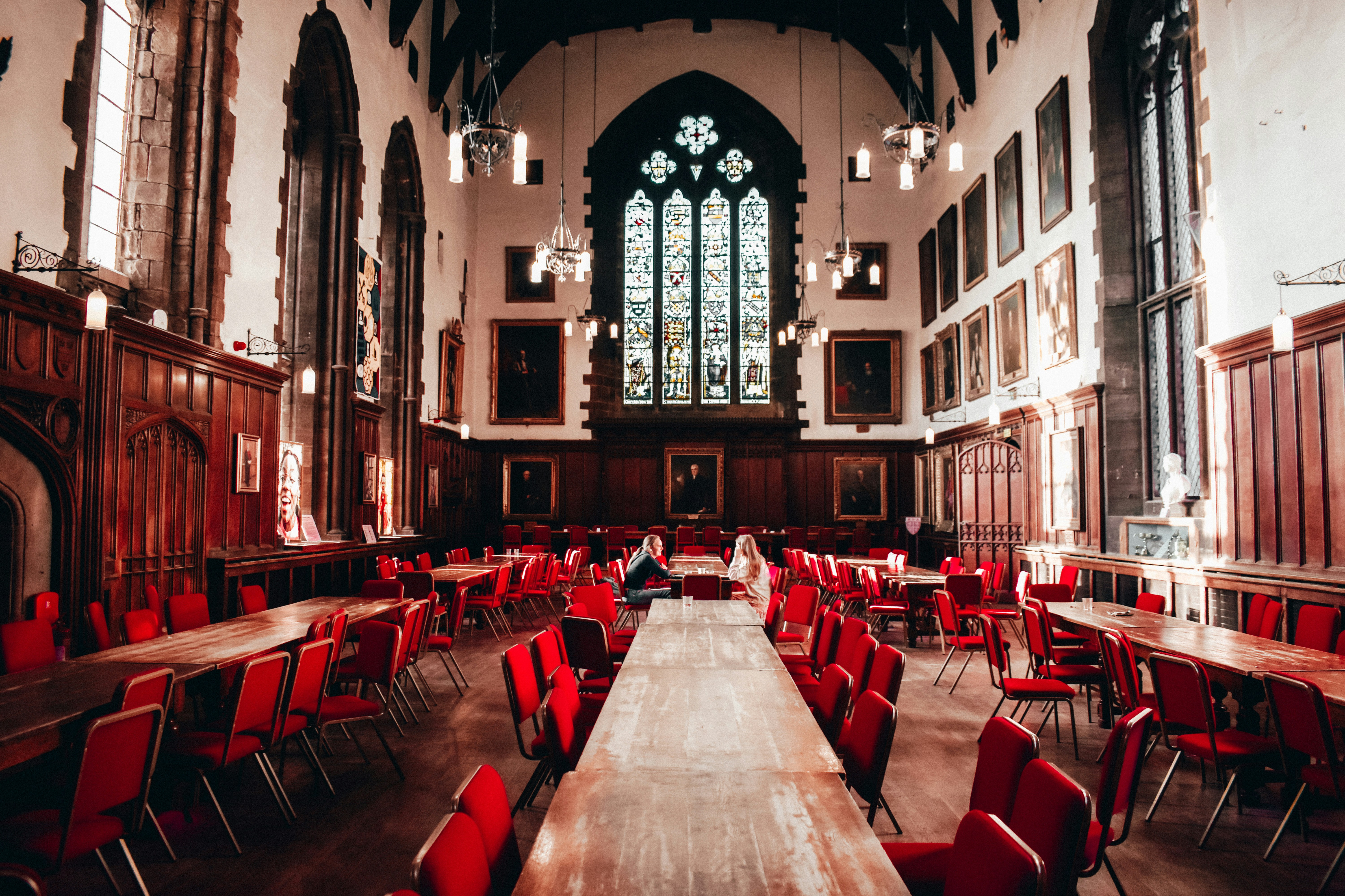 Symmetrical Tapestry: Red Chairs, Long Table, and Gothic Window