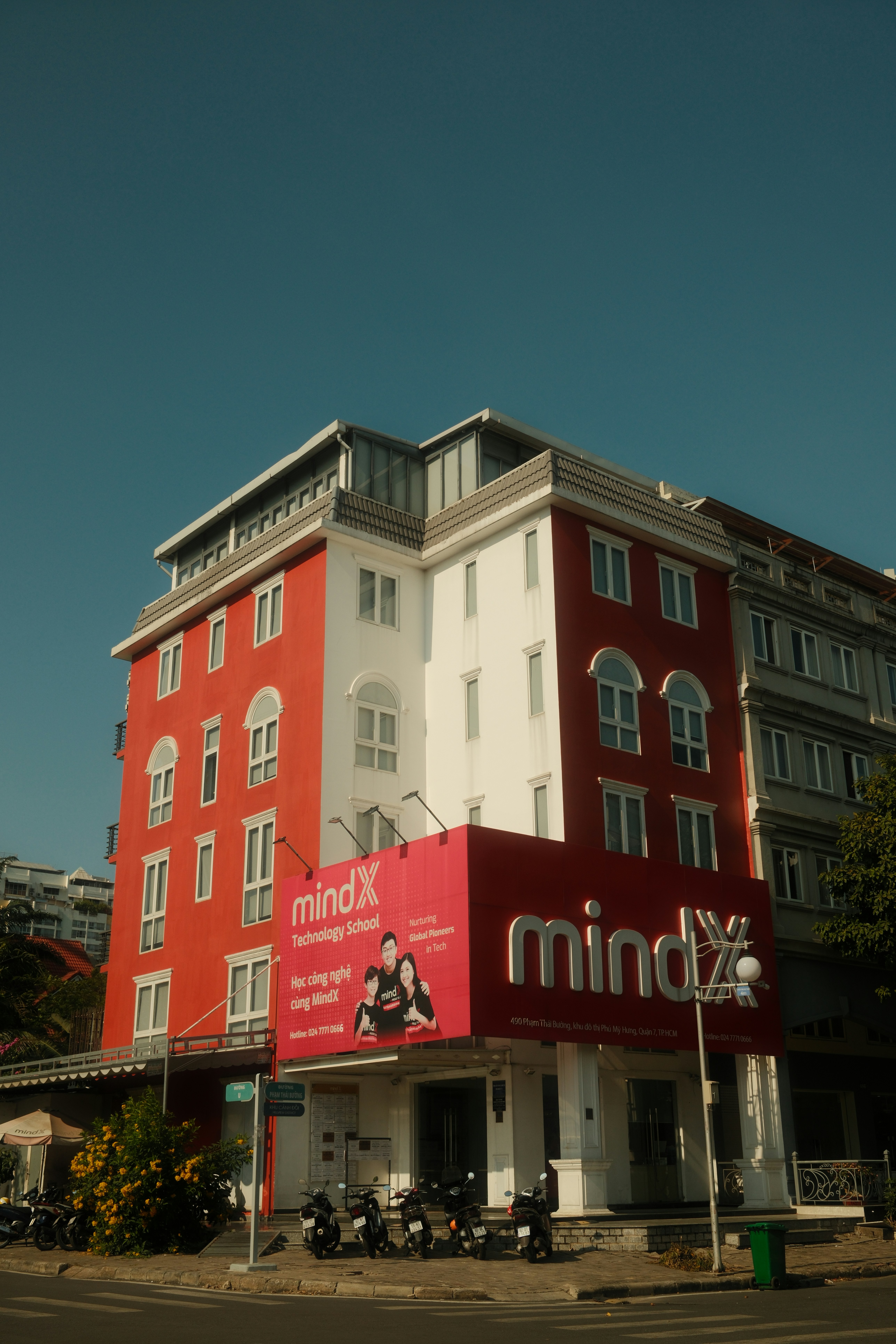 Urban Red Facade: MindX Building Under a Clear Blue Sky