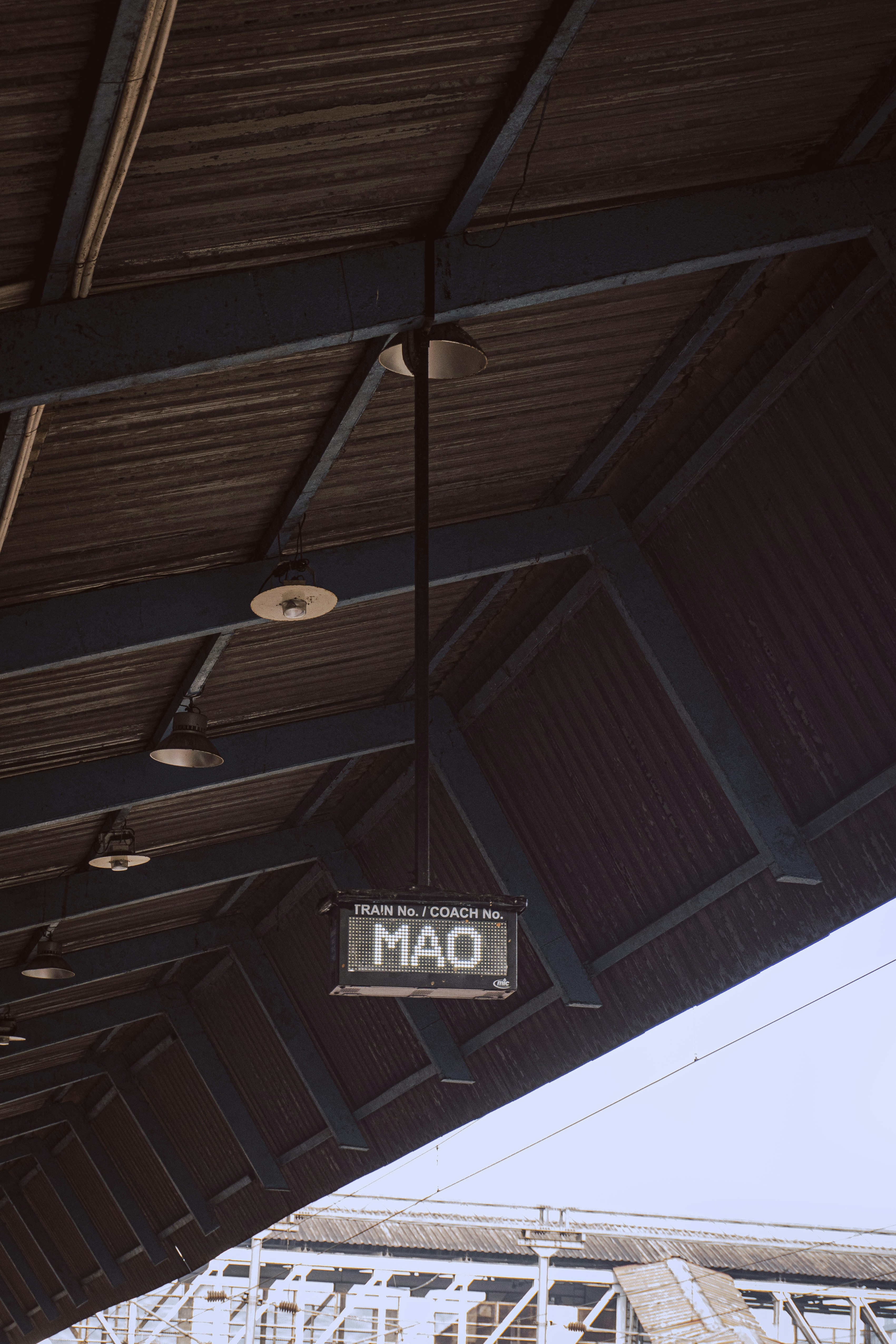 Under the Overhead Rails: A Quiet Station Sign in Dim Light