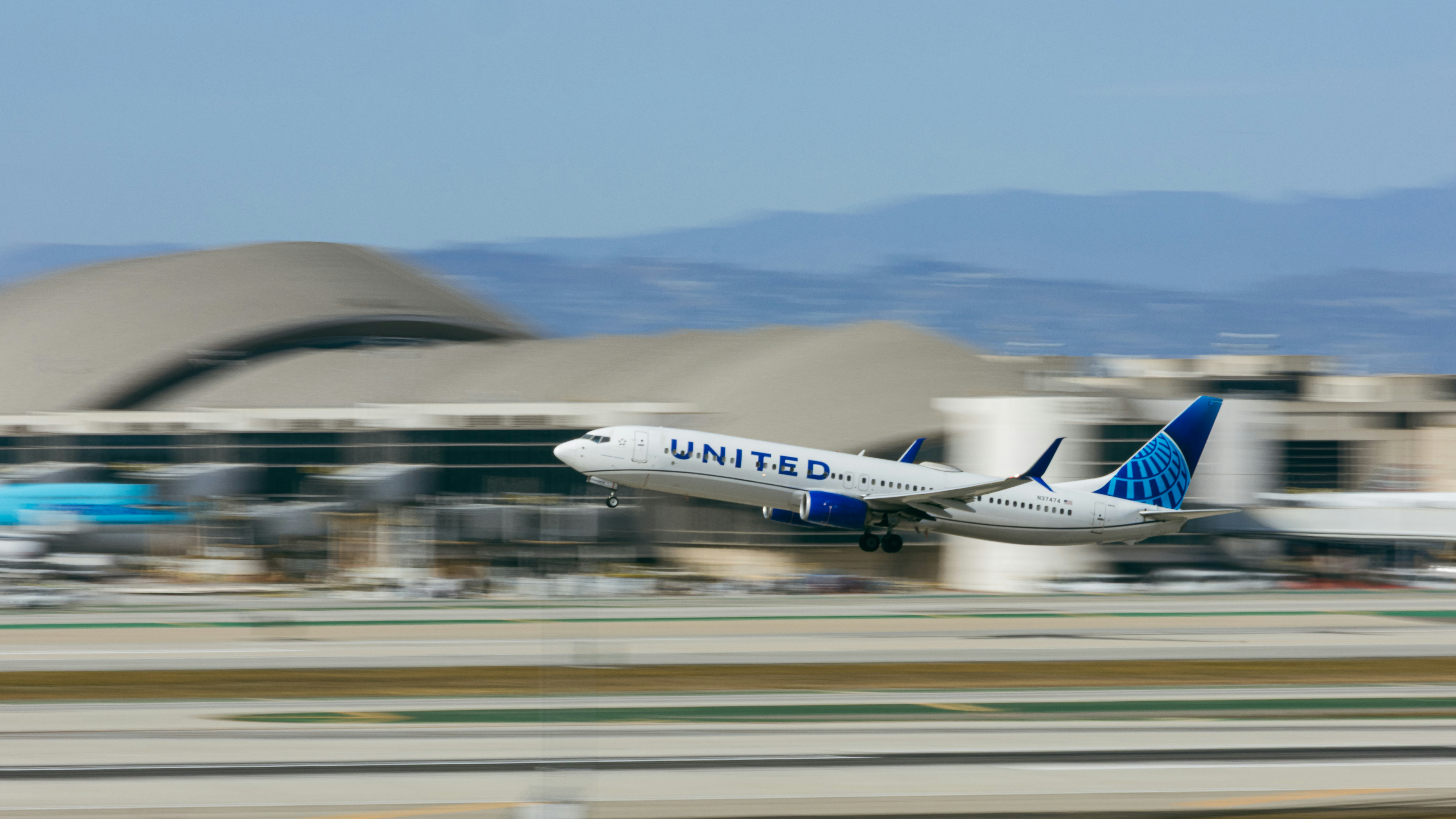 United in Motion: A United Airlines jet lifts off under a curved airport canopy