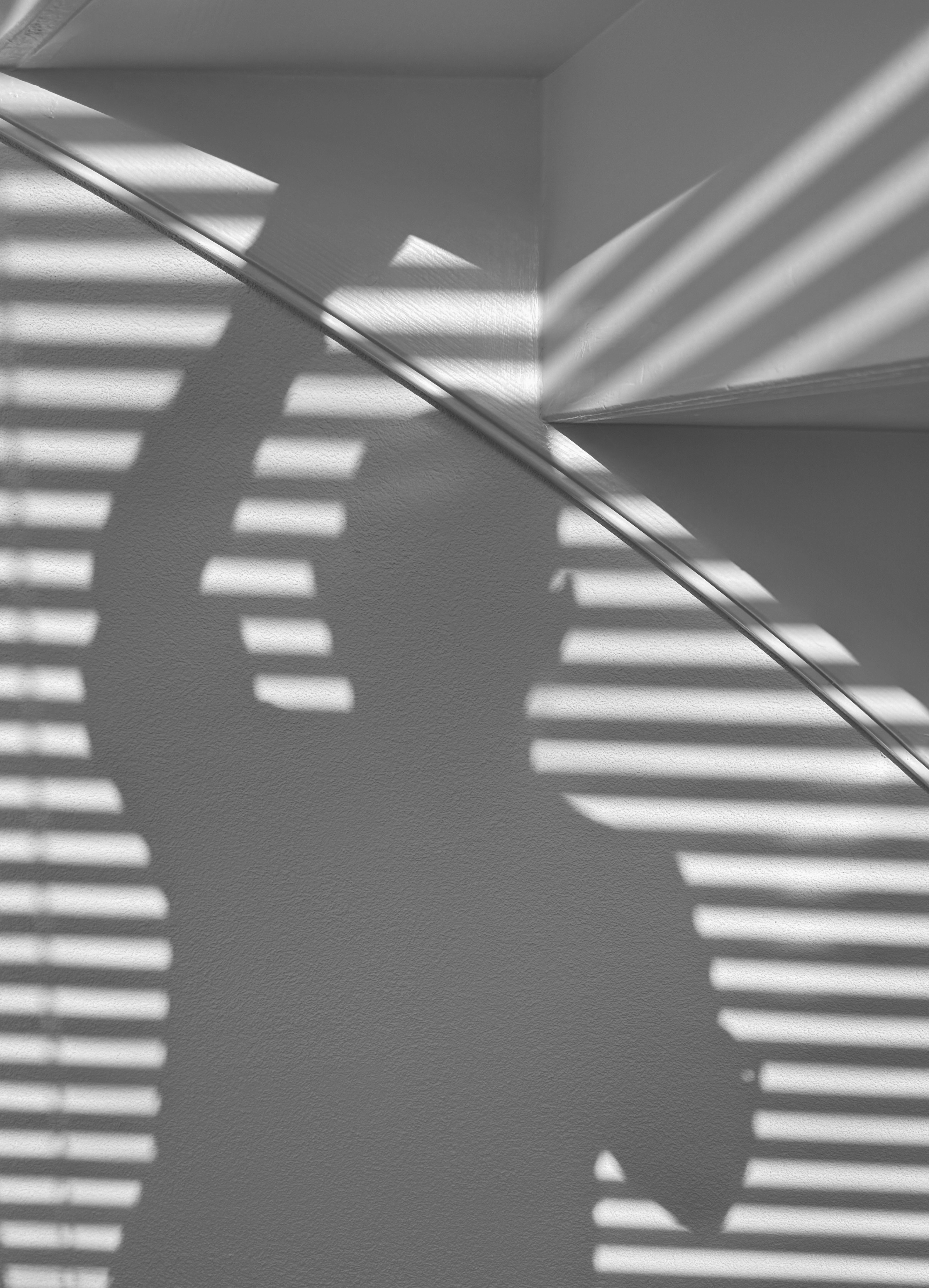 Shadowed Rhythms: Light Stripes Across a Curved Stair