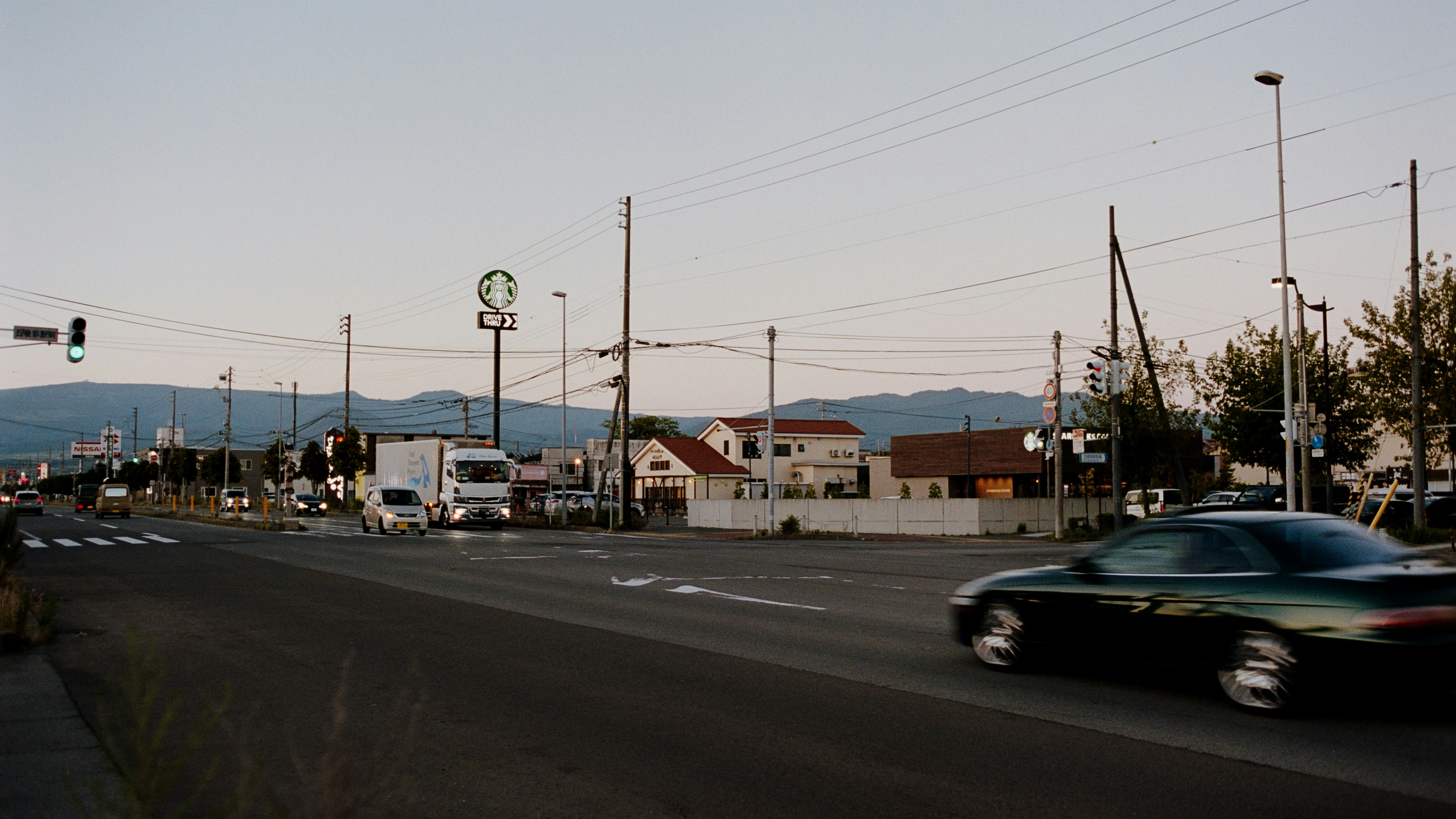 Rush Hour on a Quiet Main Street as Hills Fade in the Distance