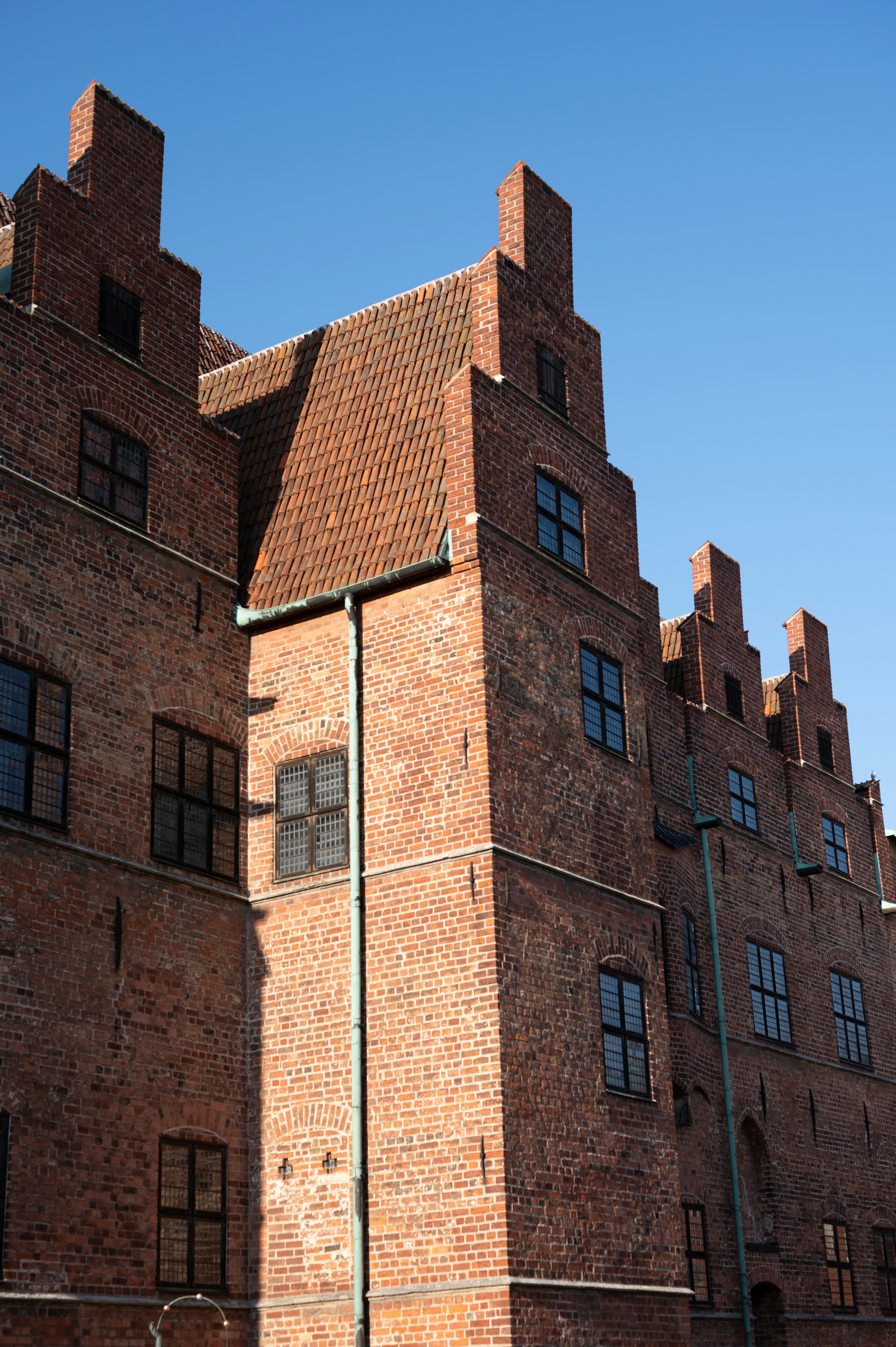 Brick Skyline: Gabled Brick Factory Under a Clear Blue Sky