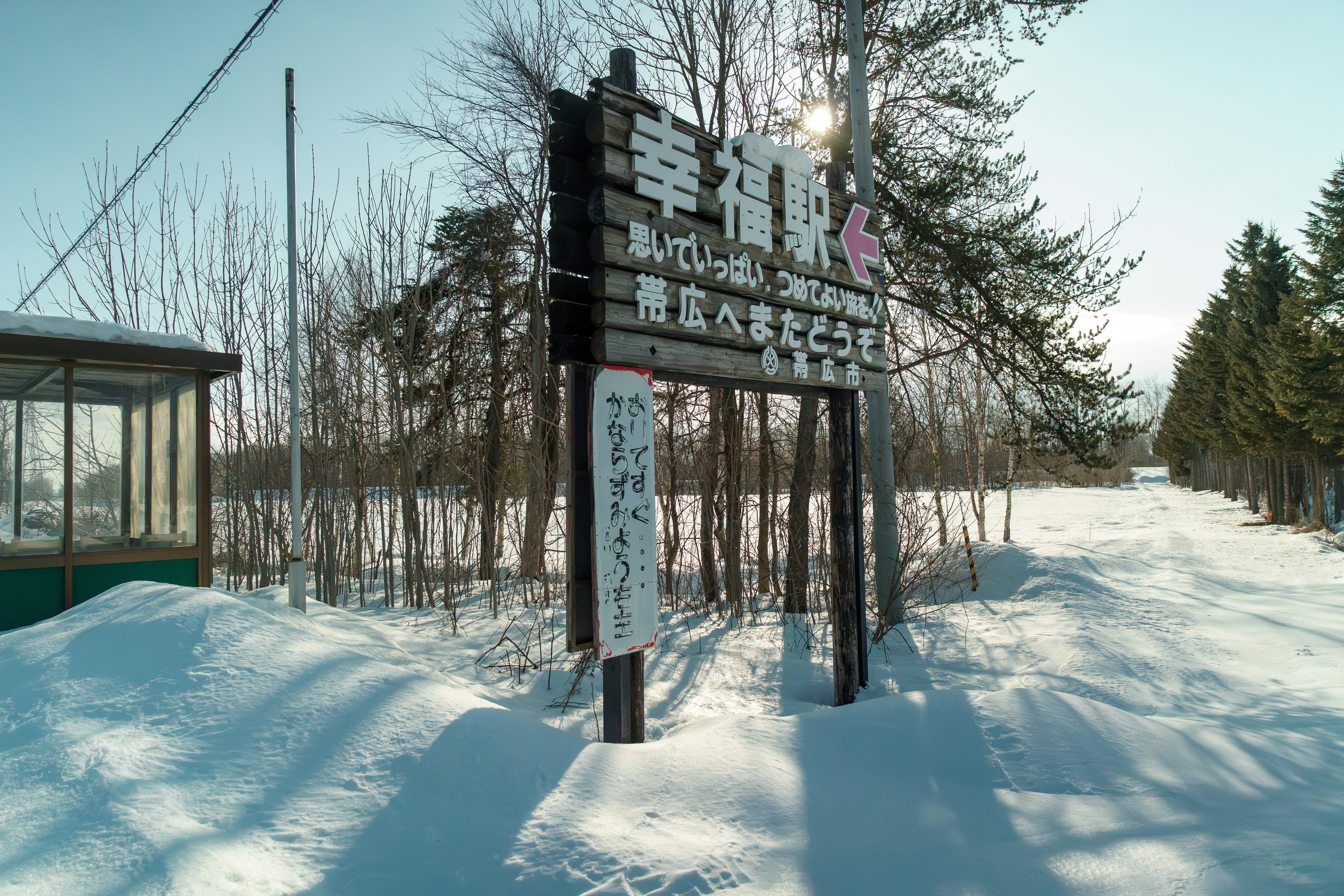 Snow-Covered Trail to a Wooden Sign in Winter Light
