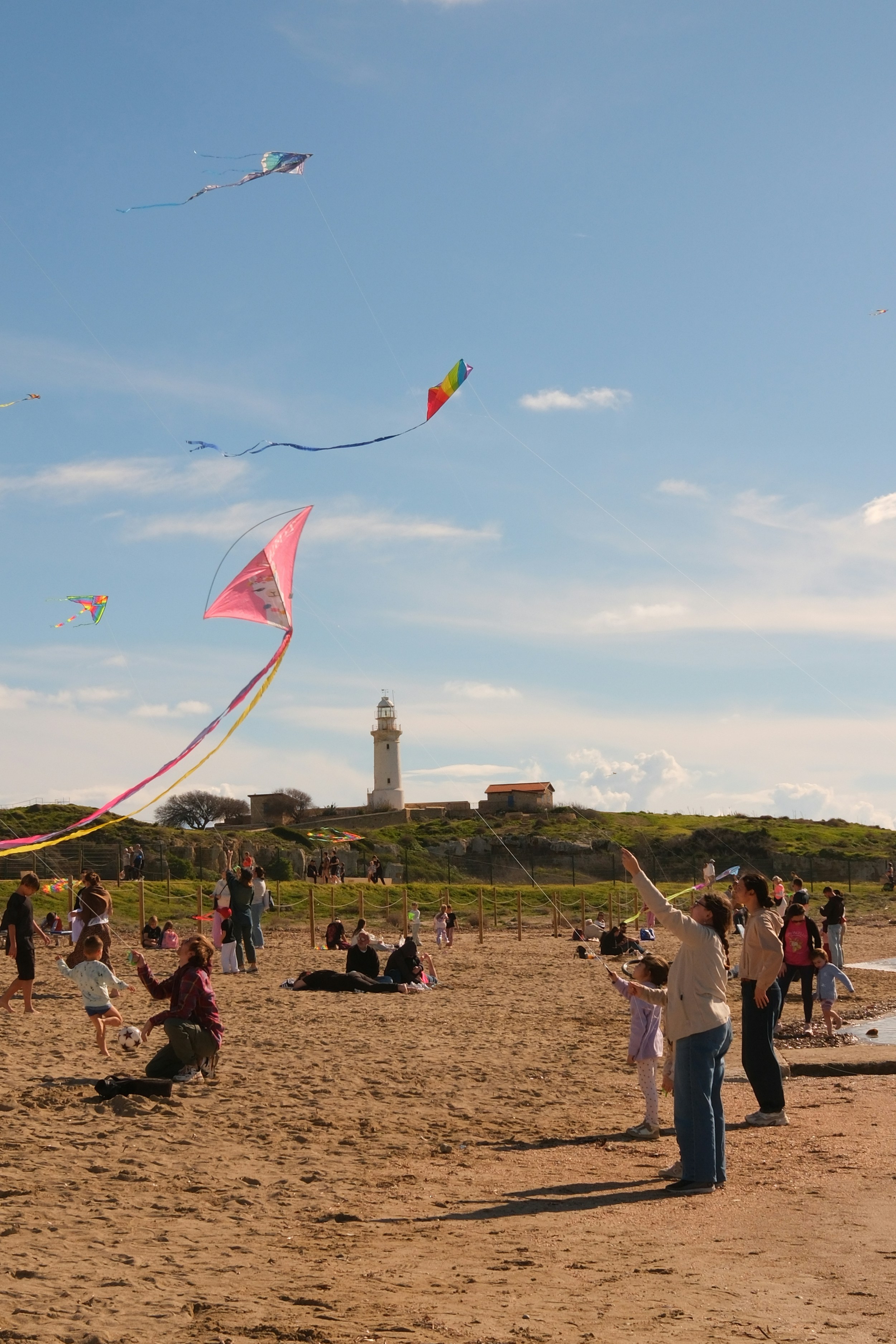Kite flight over sunlit shore with a lighthouse watch