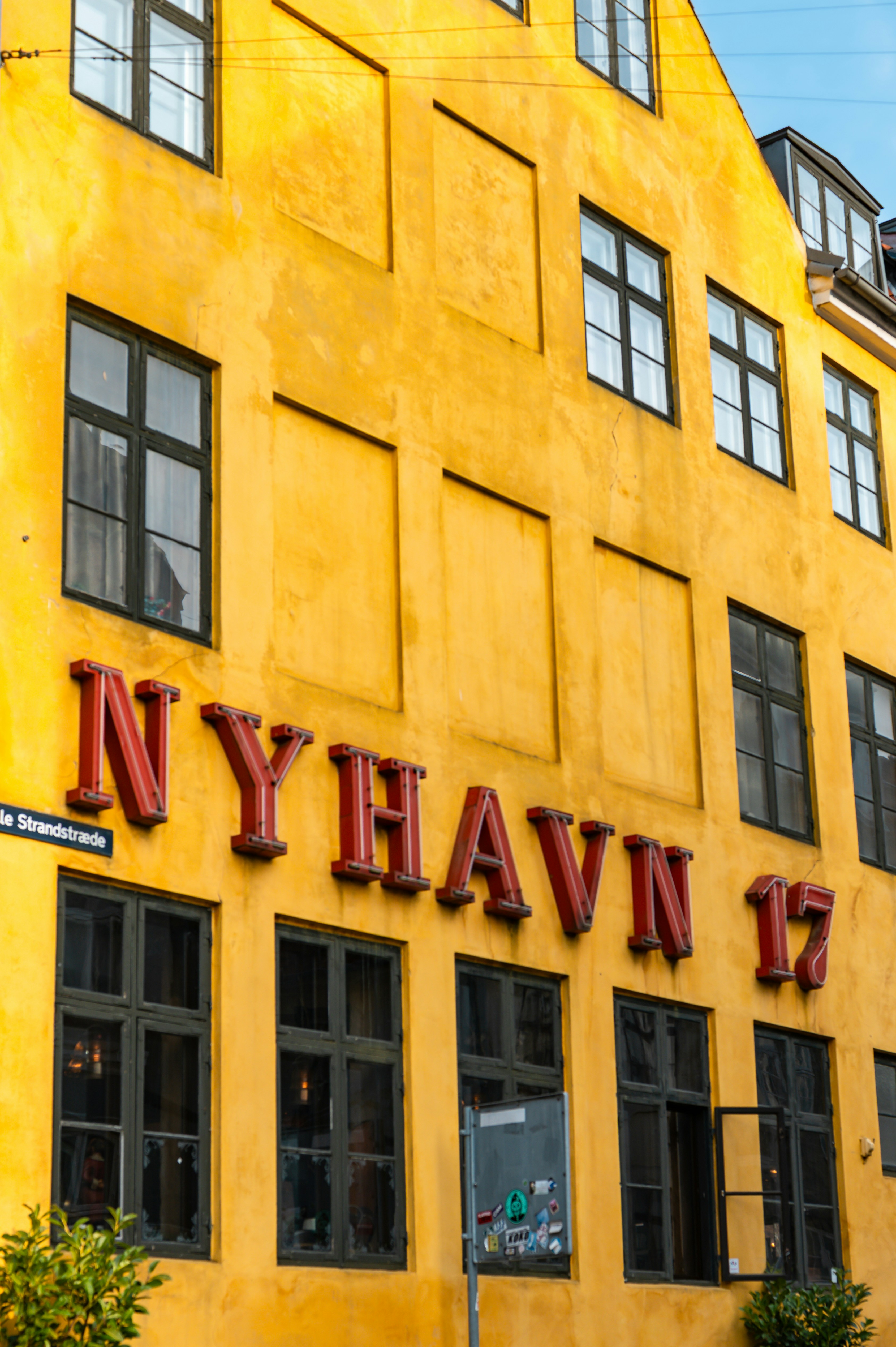Golden Facade of Nyhavn 17: Bold Yellow Blocks and Red Signage