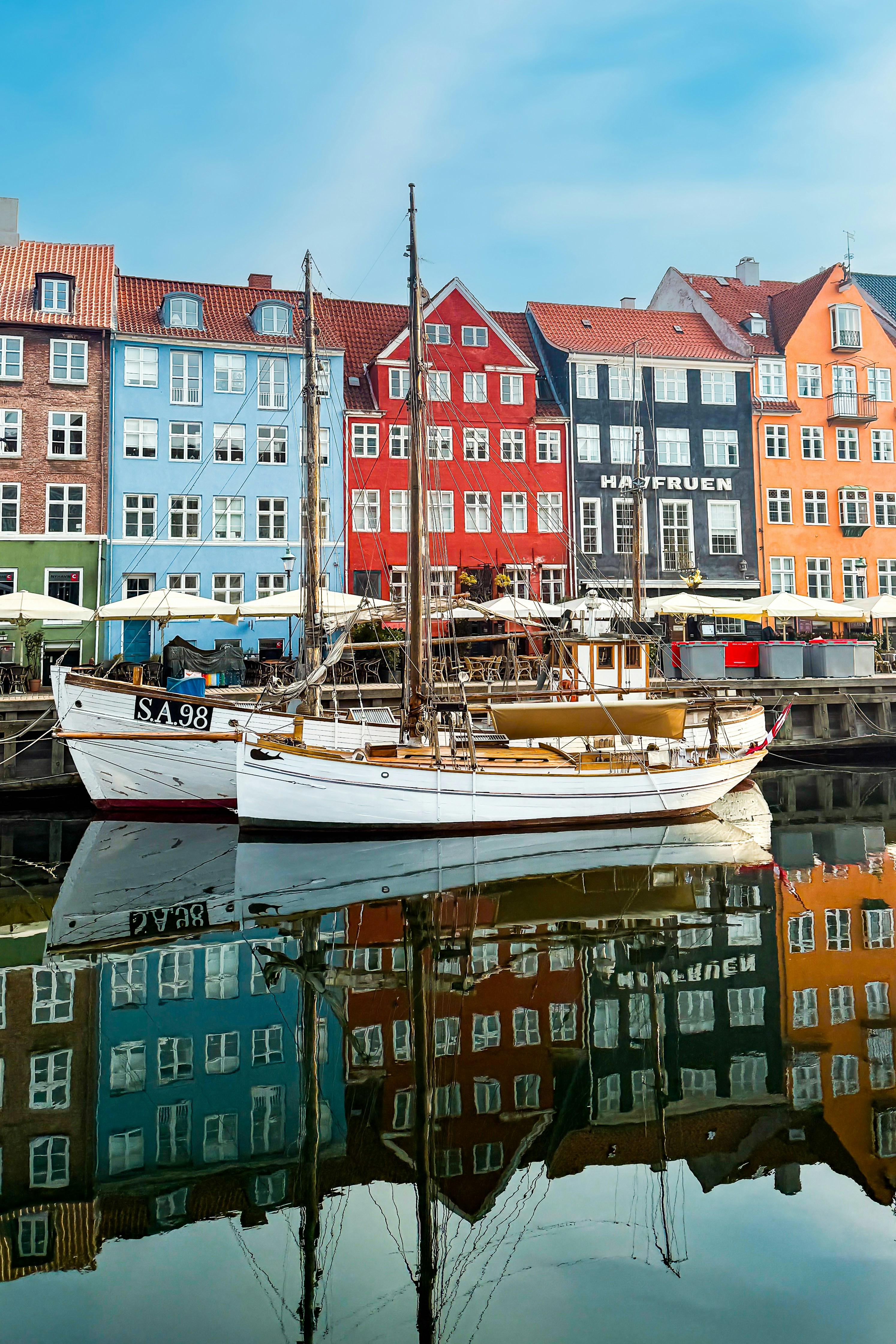 Colorful waterfront: boats and mirrored houses in Nyhavn-inspired harbor
