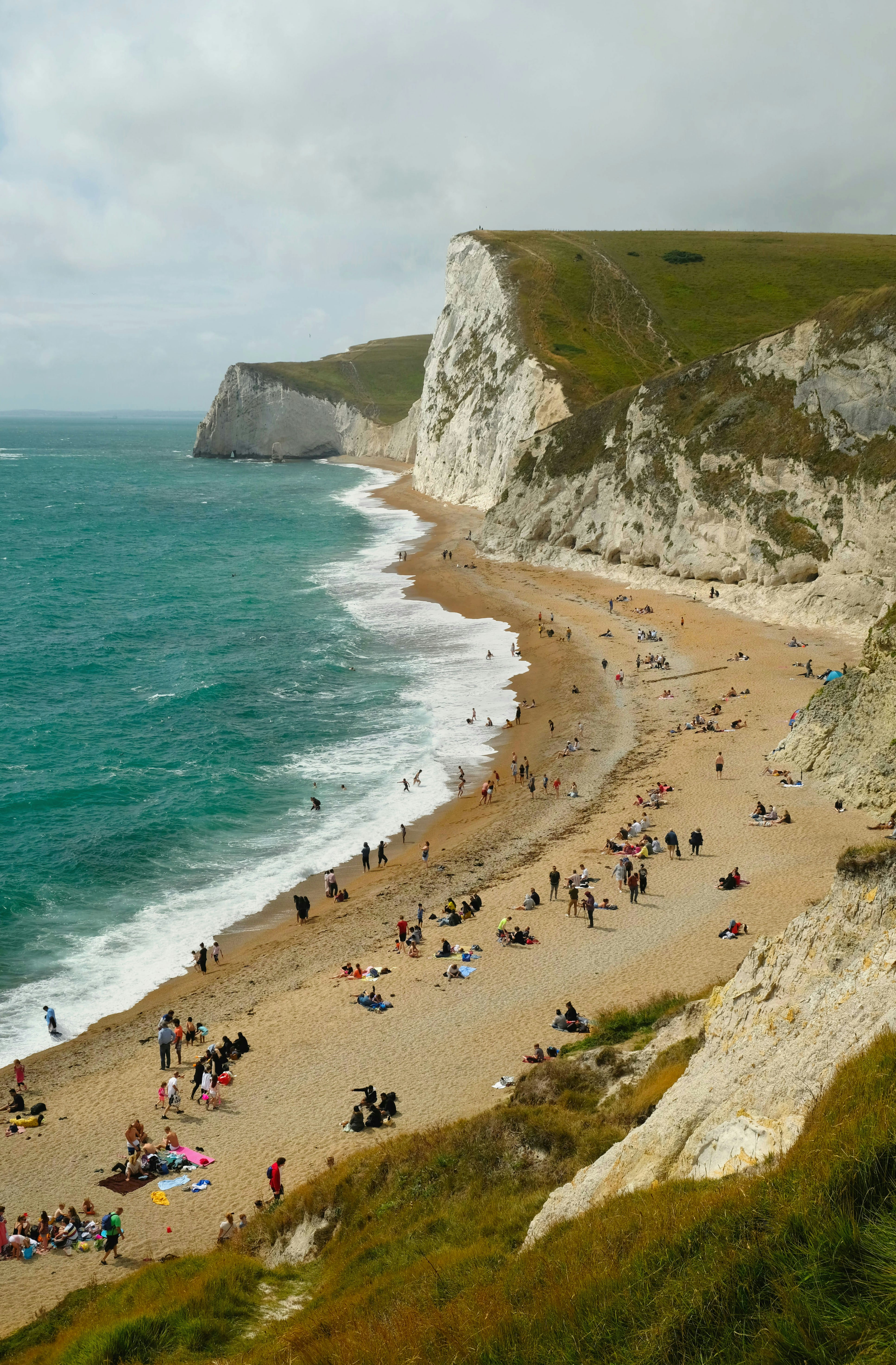 Cliffside Beachline: People Appear as Tiny Dots Along the White Chalk and Turquoise Sea