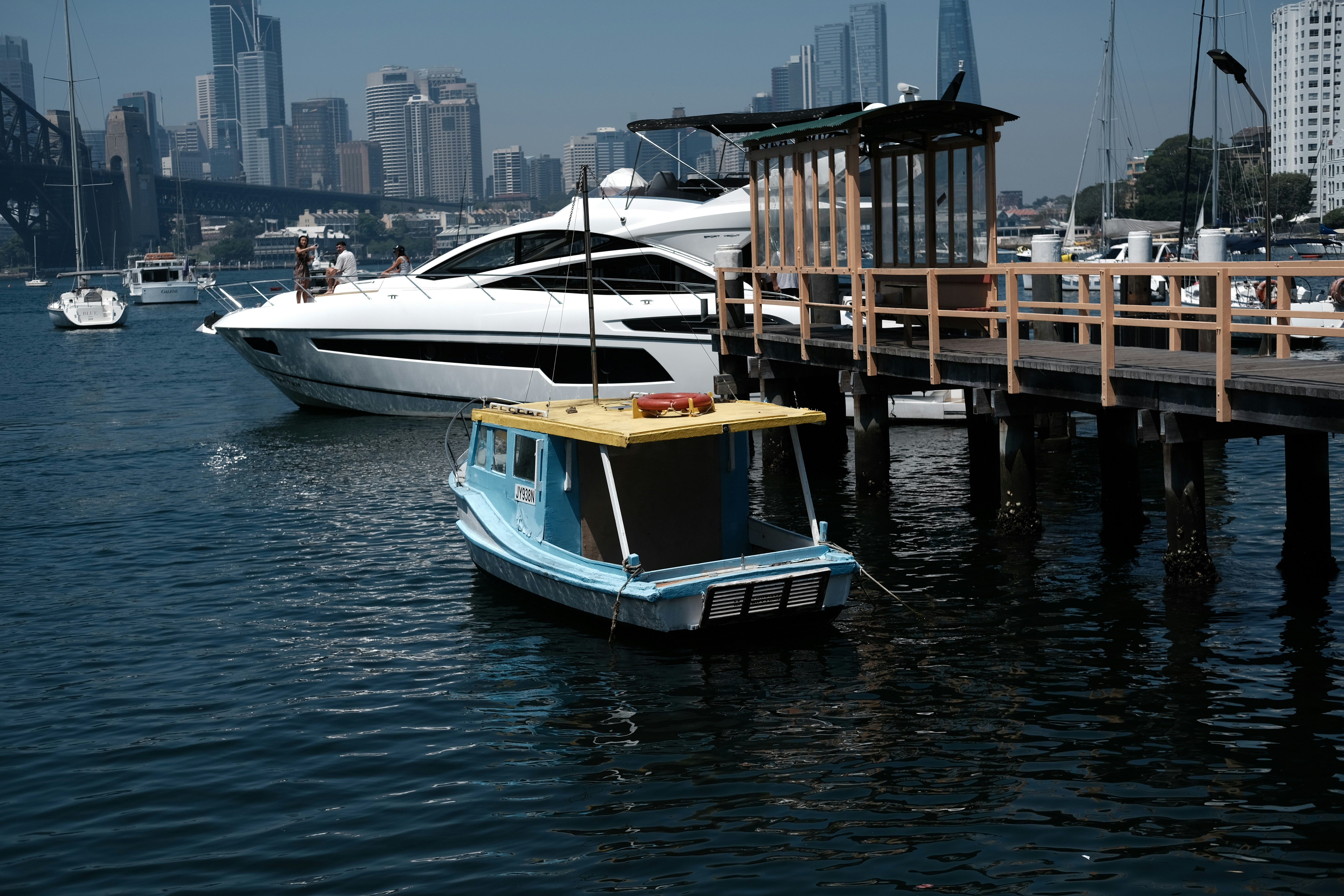 Docked Delights: A Coastal Scene of Yachts and a Tiny Blue Boat