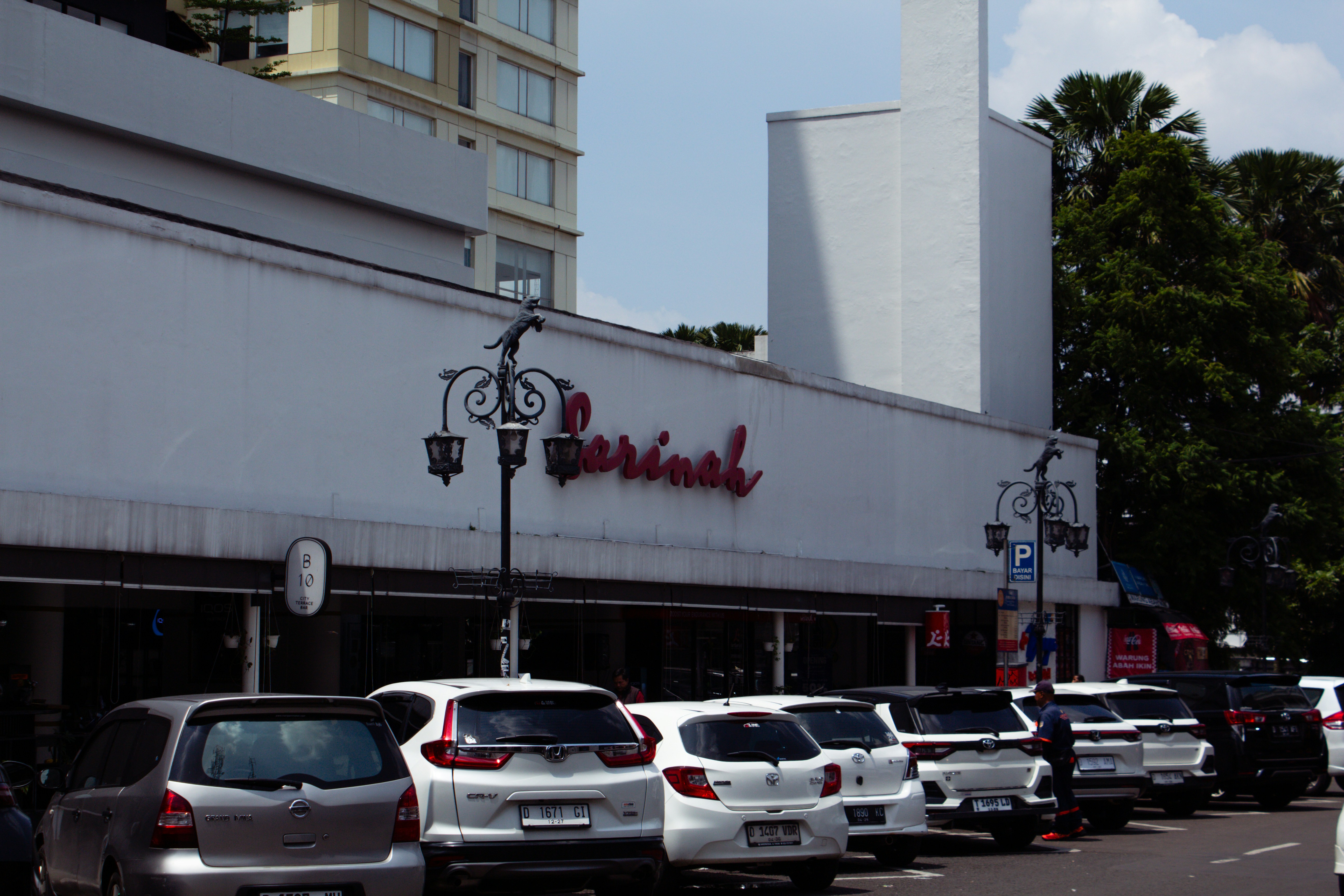 Lot of Cars Parked in Front of a Shopping Center with Red Sign