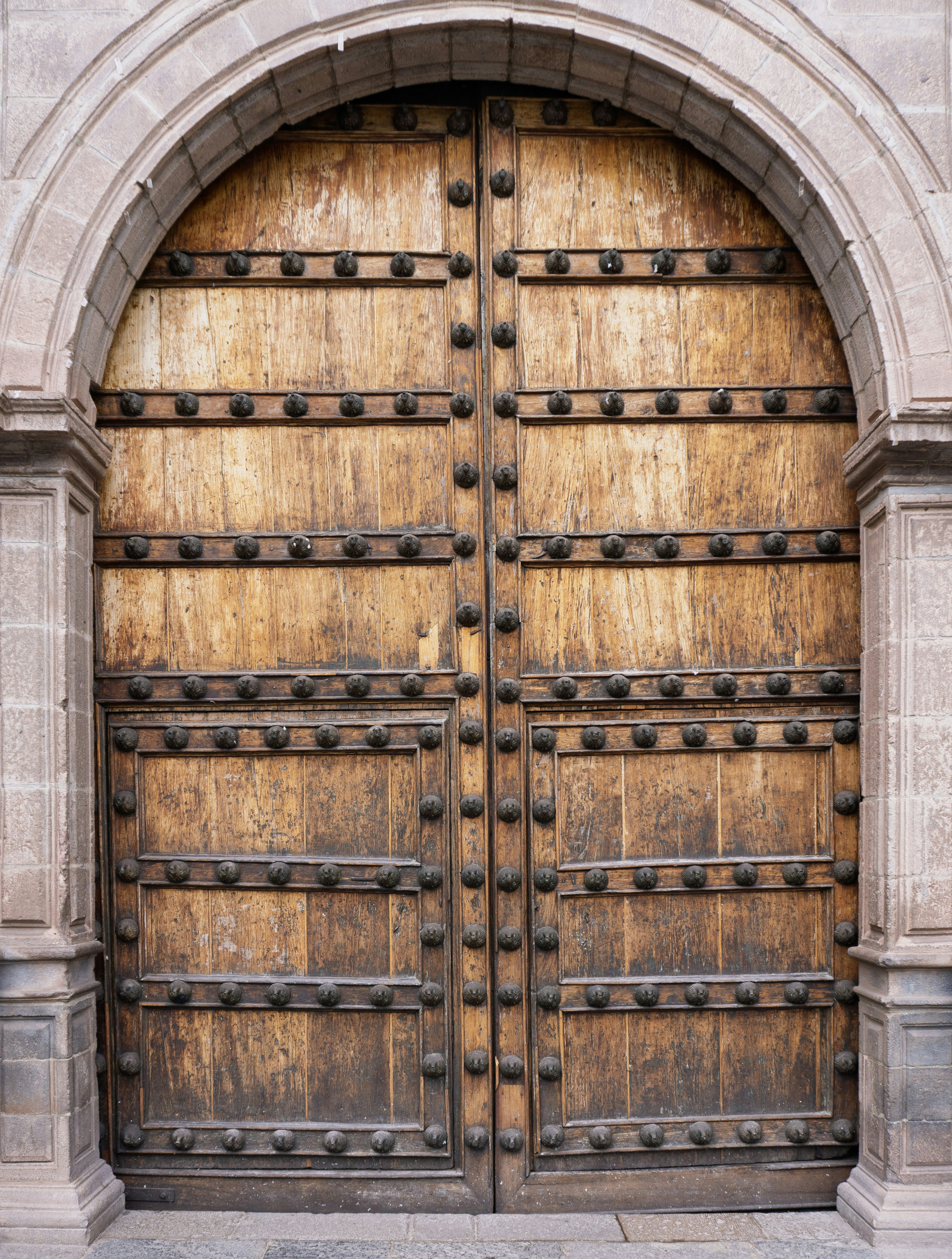 Rugged Iron-studded Carved Doors Framing a Stone Arch