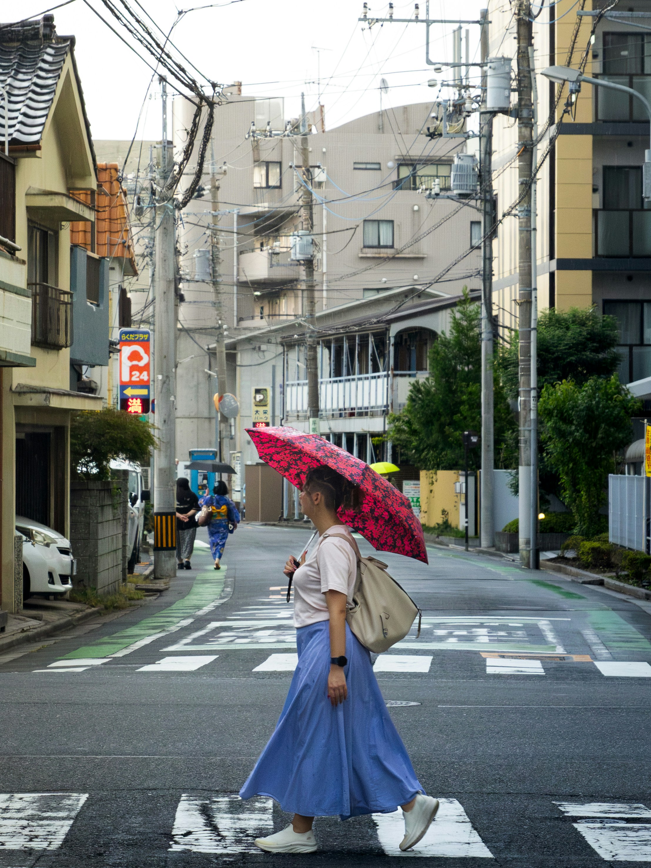 Crosswalk Moment: A Woman with a Pink Umbrella Walks Through a Quiet Urban Street