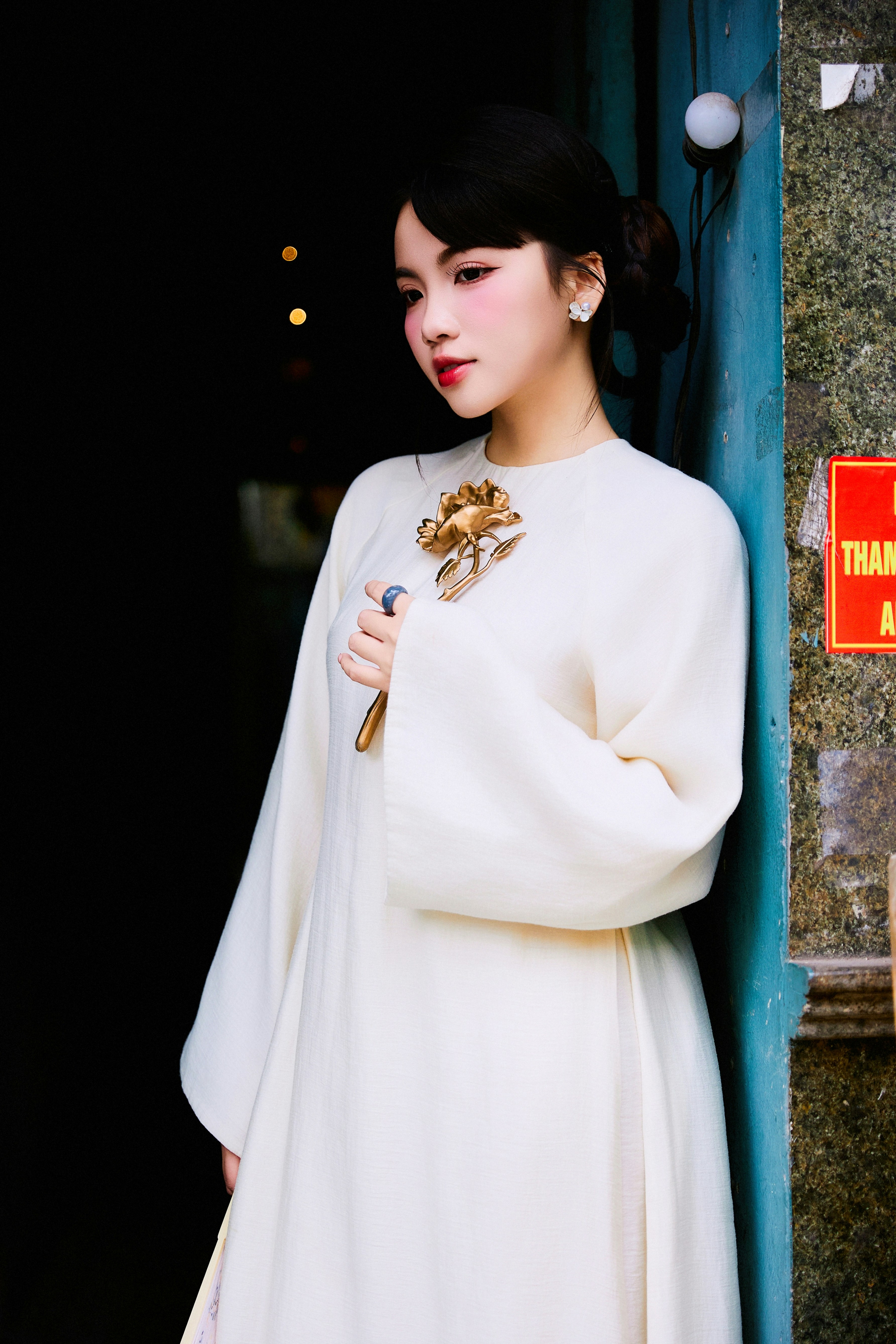 White elegance against teal doorway: a poised portrait with a floral accent
