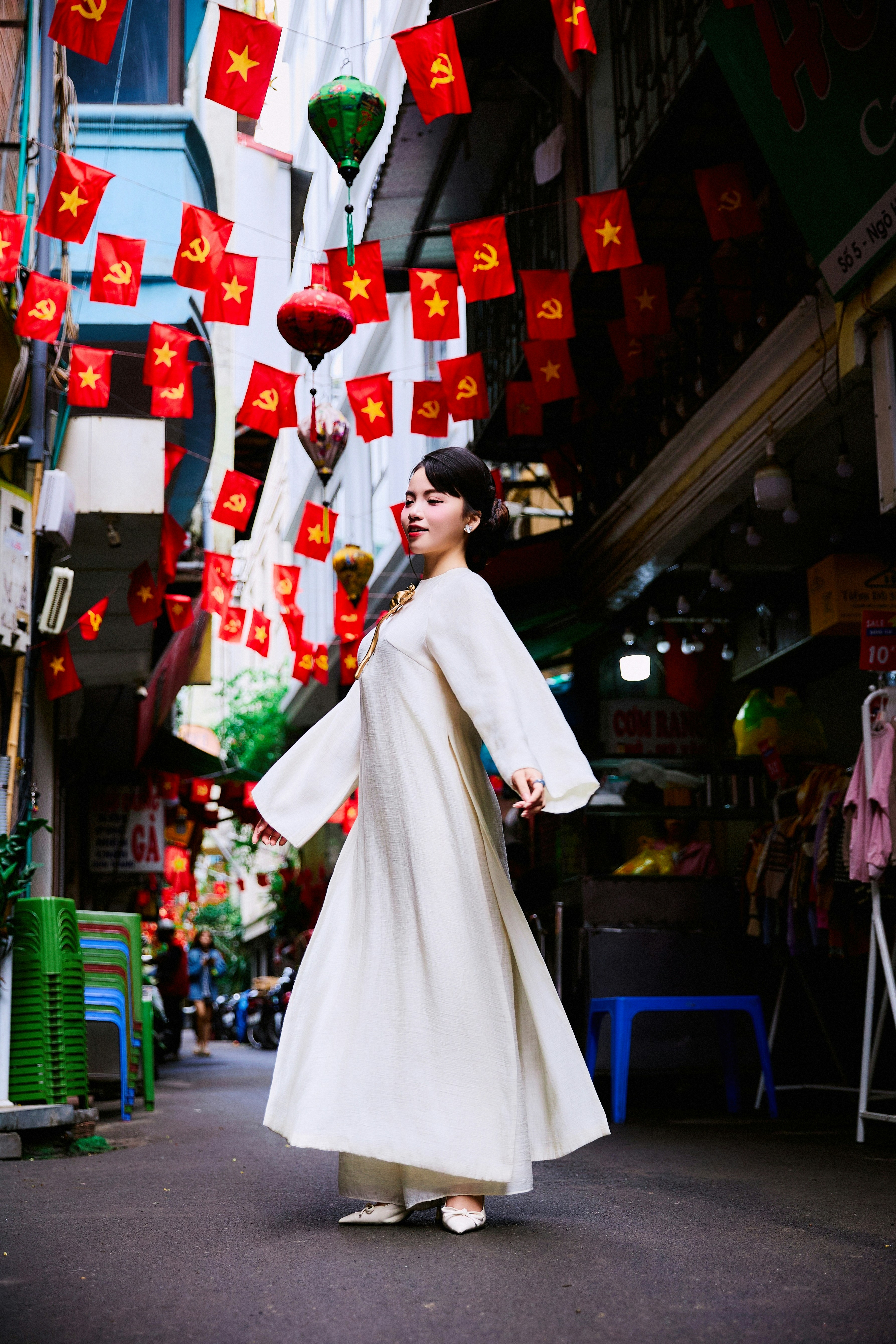 Elegance in a Lantern-lit Alley: A Woman in White Dancing Amid Vietnamese Flags