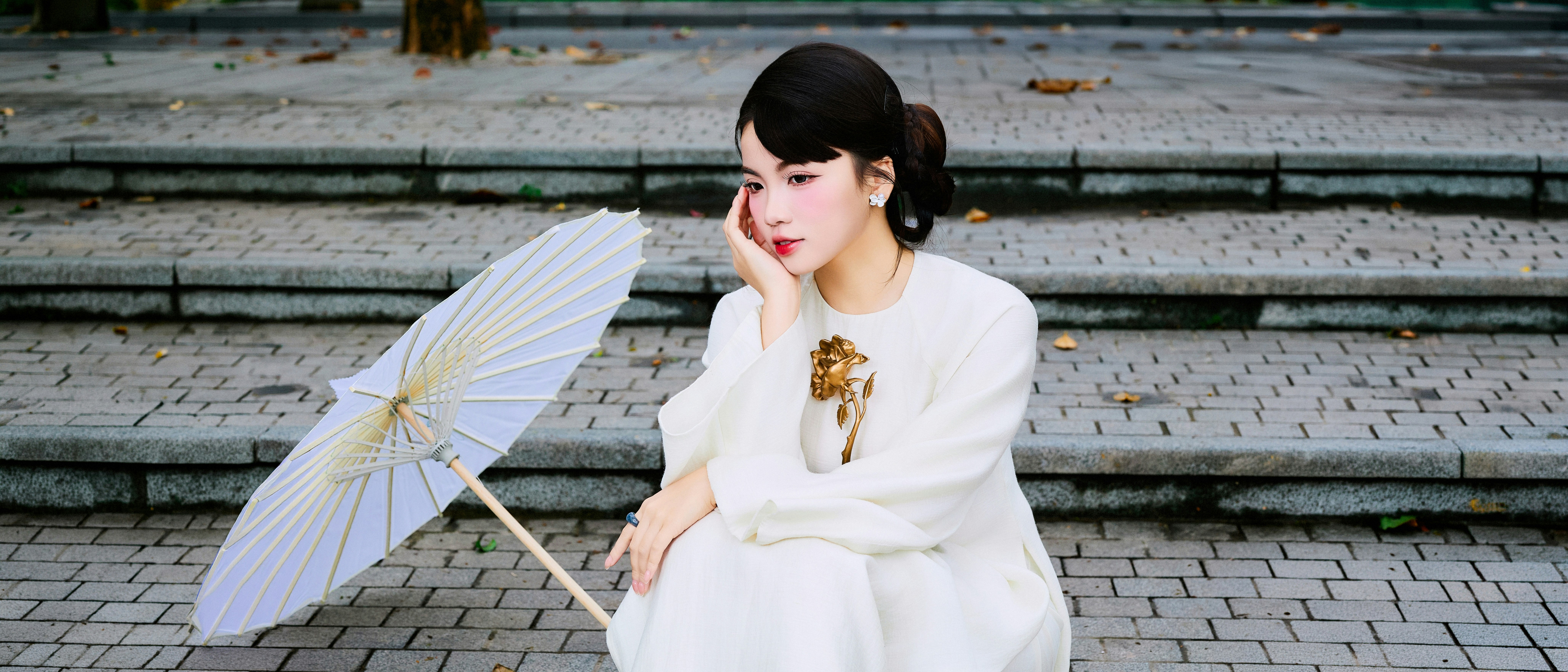 Quiet Moment in White: A Portrait on Stone Steps with a Parasol