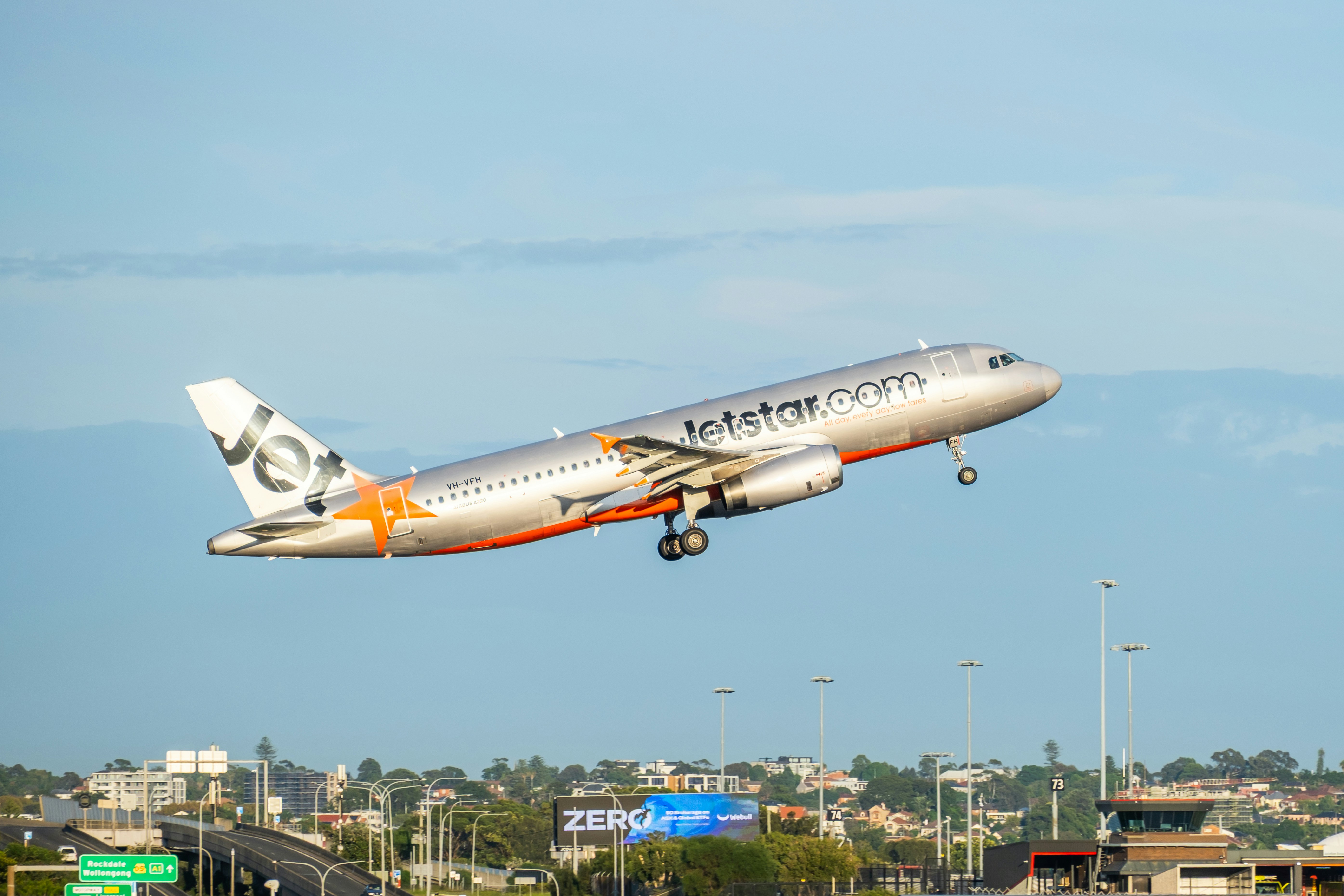 Jetstar in ascent: mid-approach over cityscape