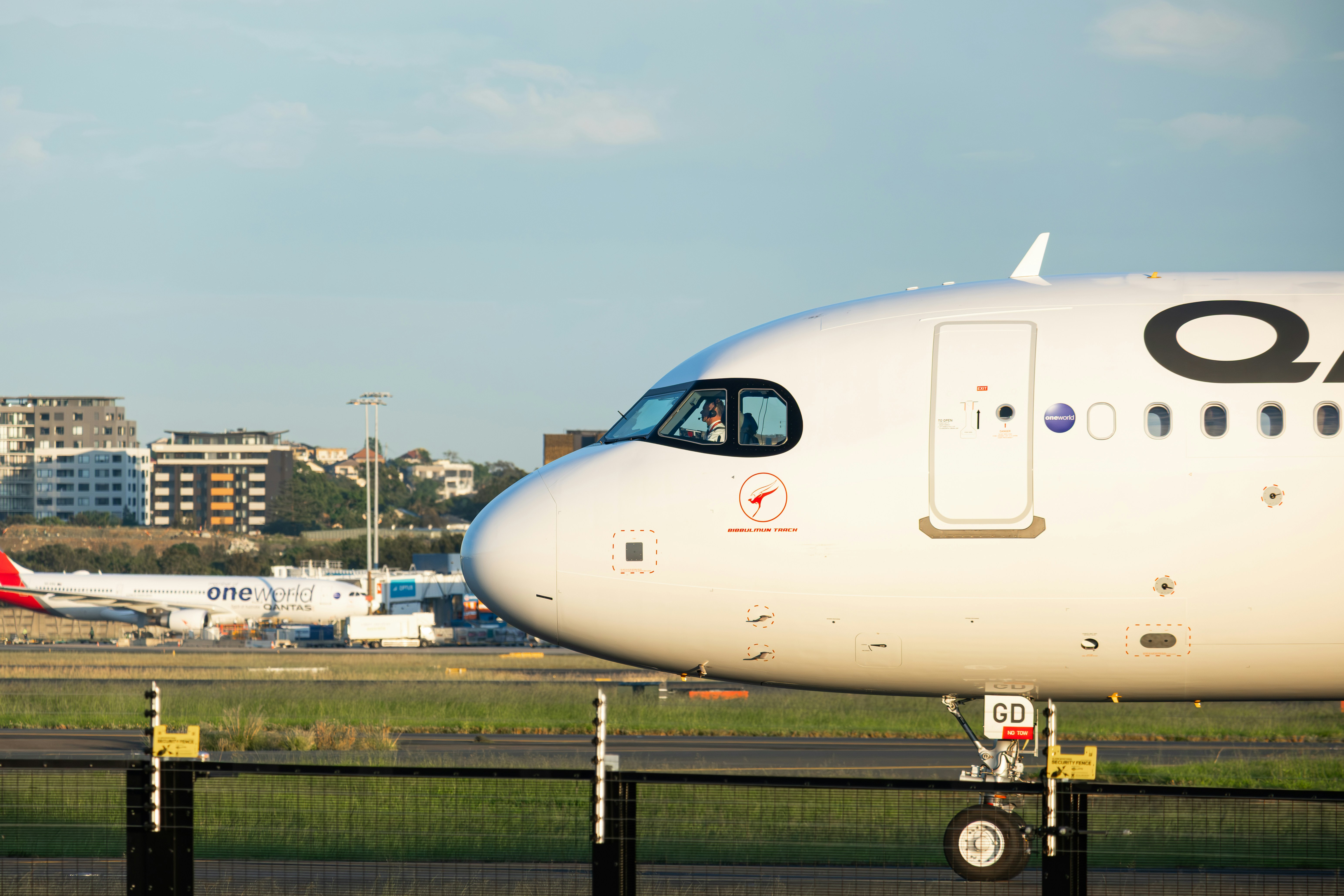 Close-up of a white aircraft nose at the gate, with terminal and tarmac in the background