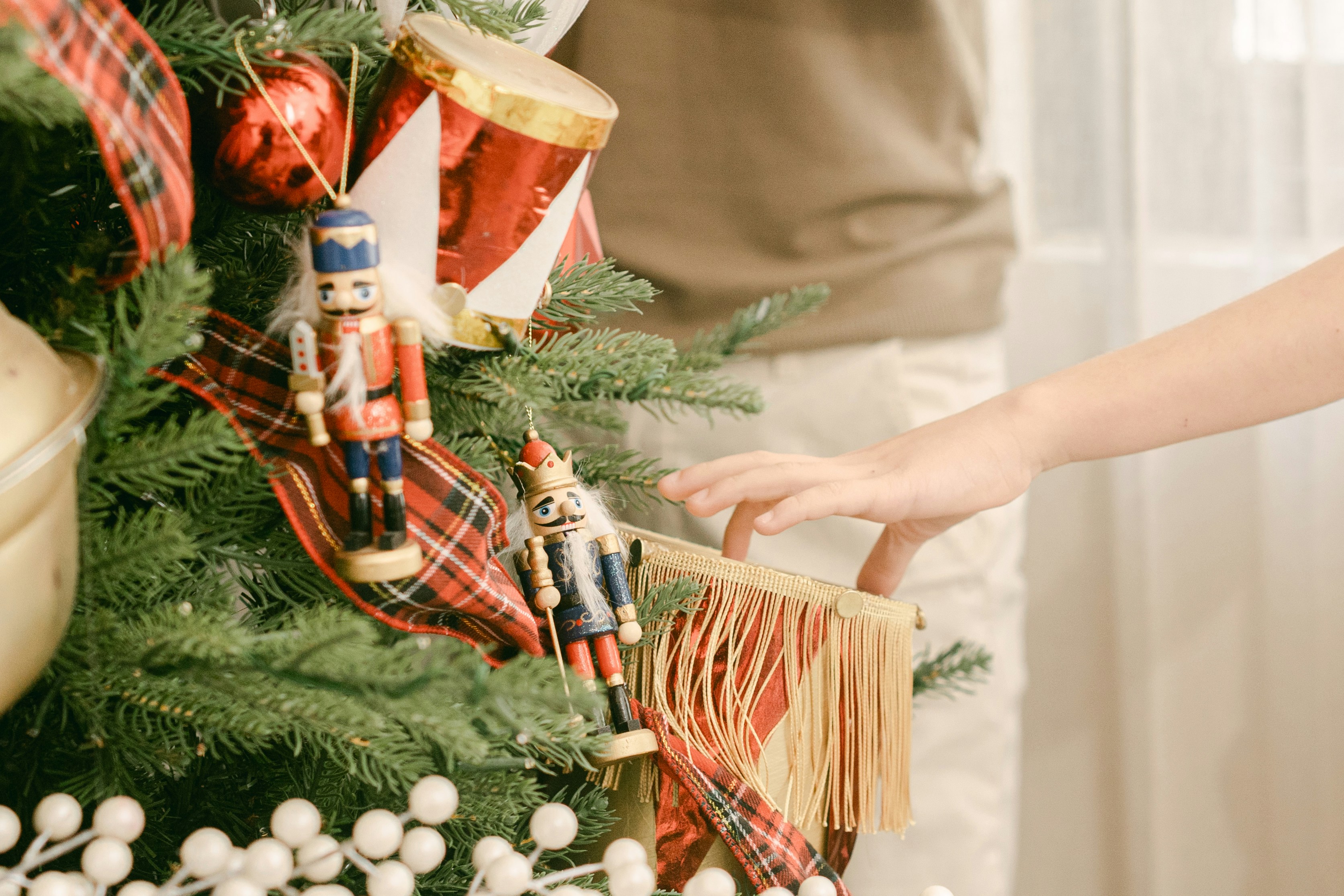 Touch of Tradition: Hand Reaches Toward a Decorated Christmas Tree