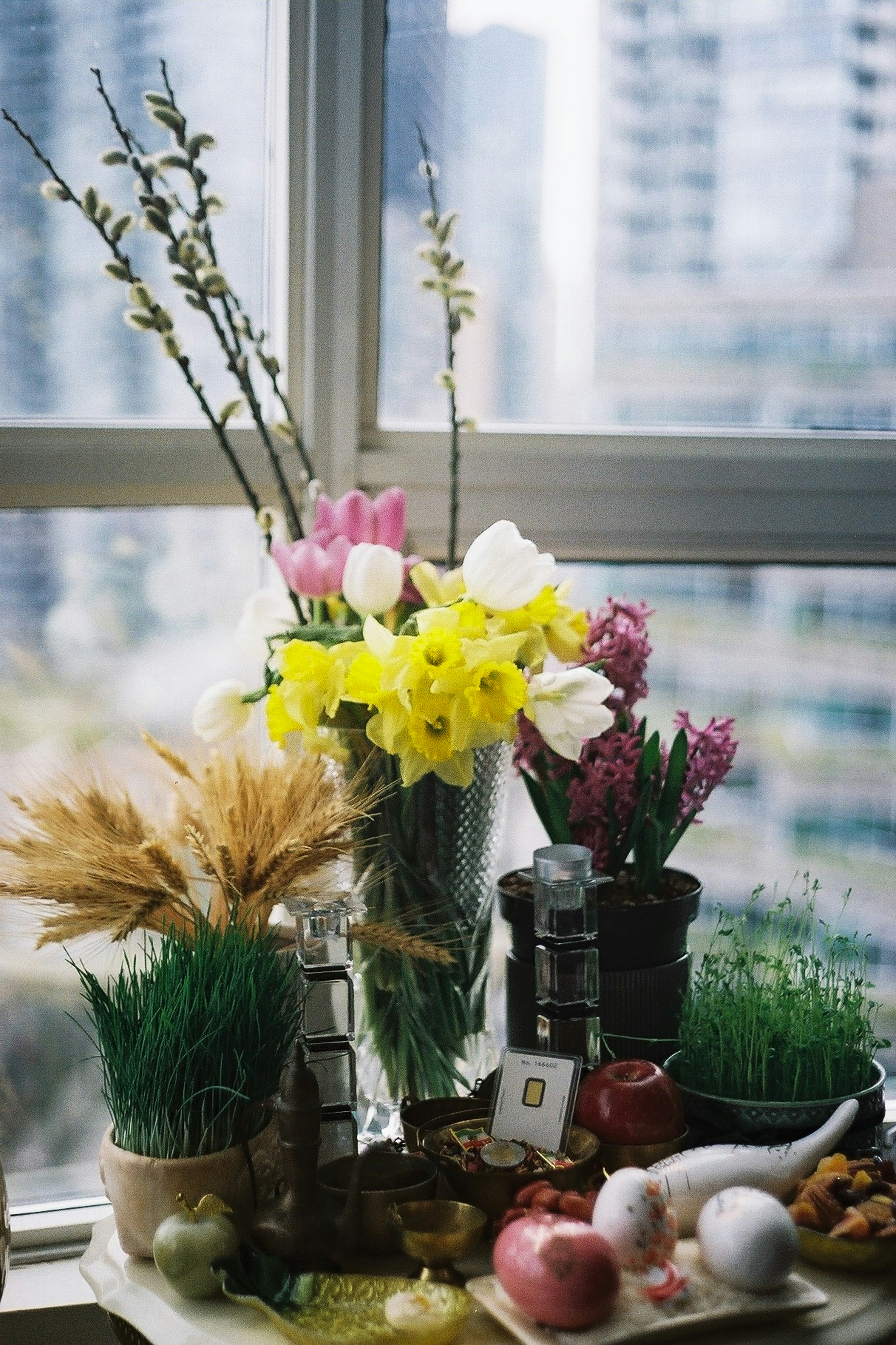Vivid still life bouquet by the window with herbal greens and tableware
