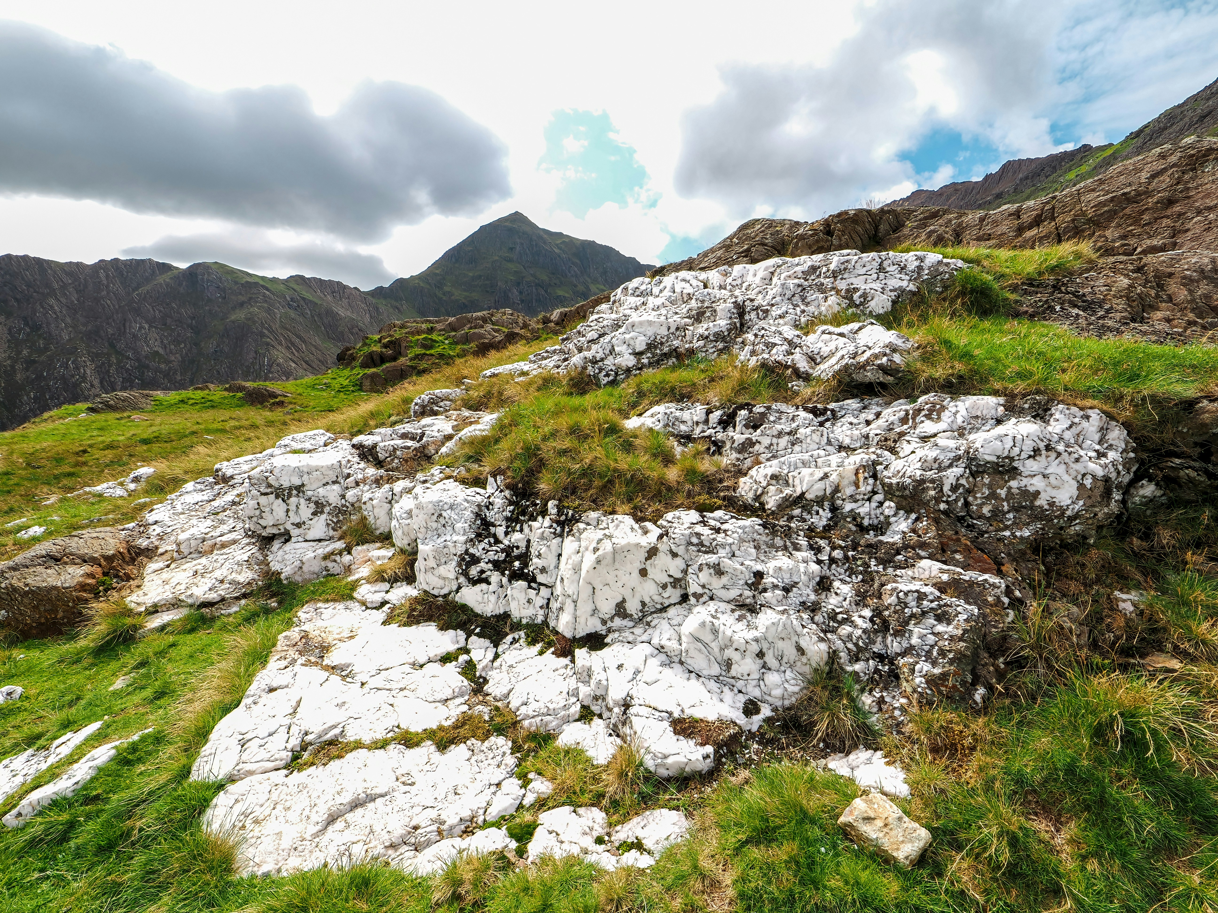 White limestone outcrop under a cloudy alpine sky