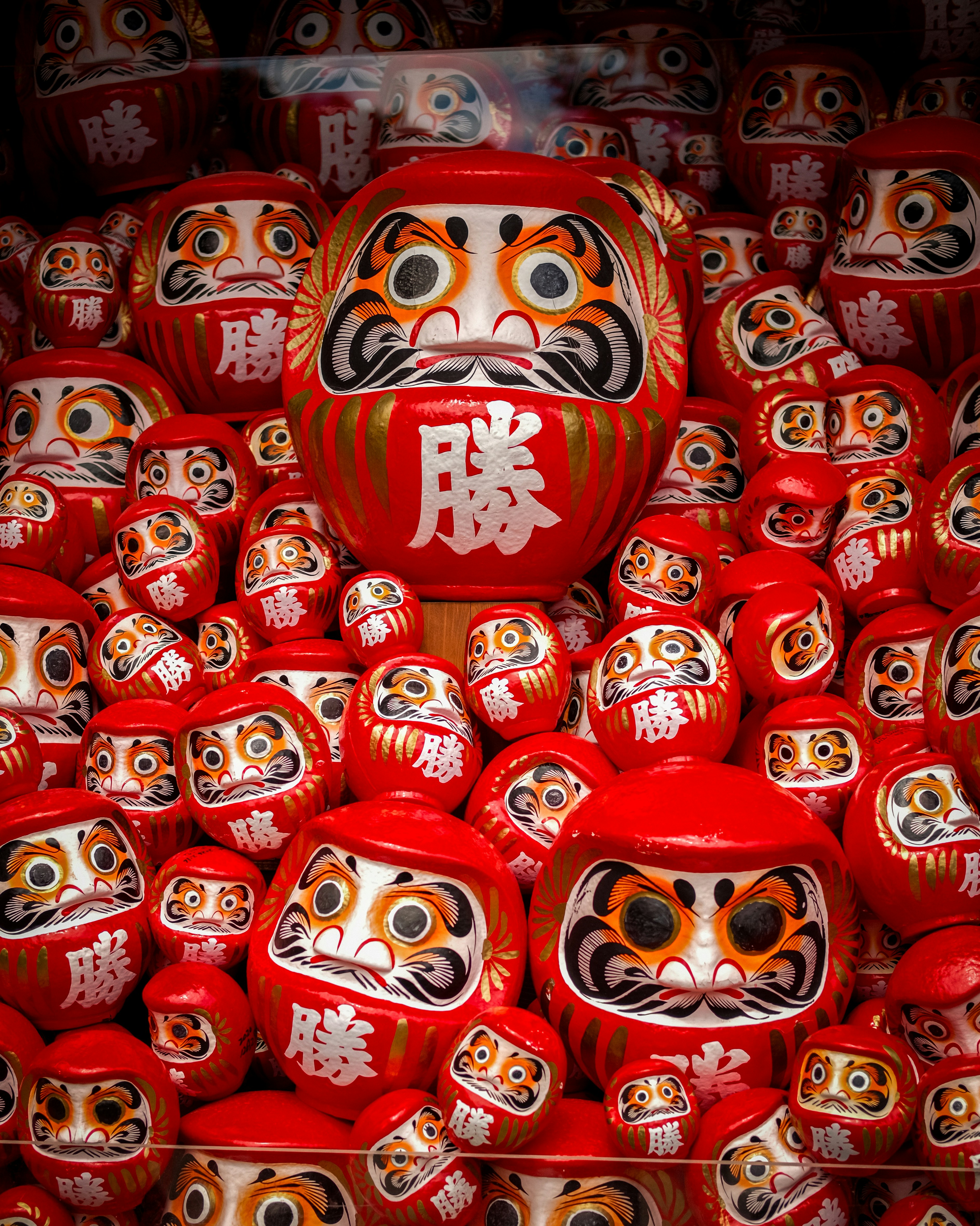 Red Dawn: A Sea of Daruma Dolls with a Dominant Central Face