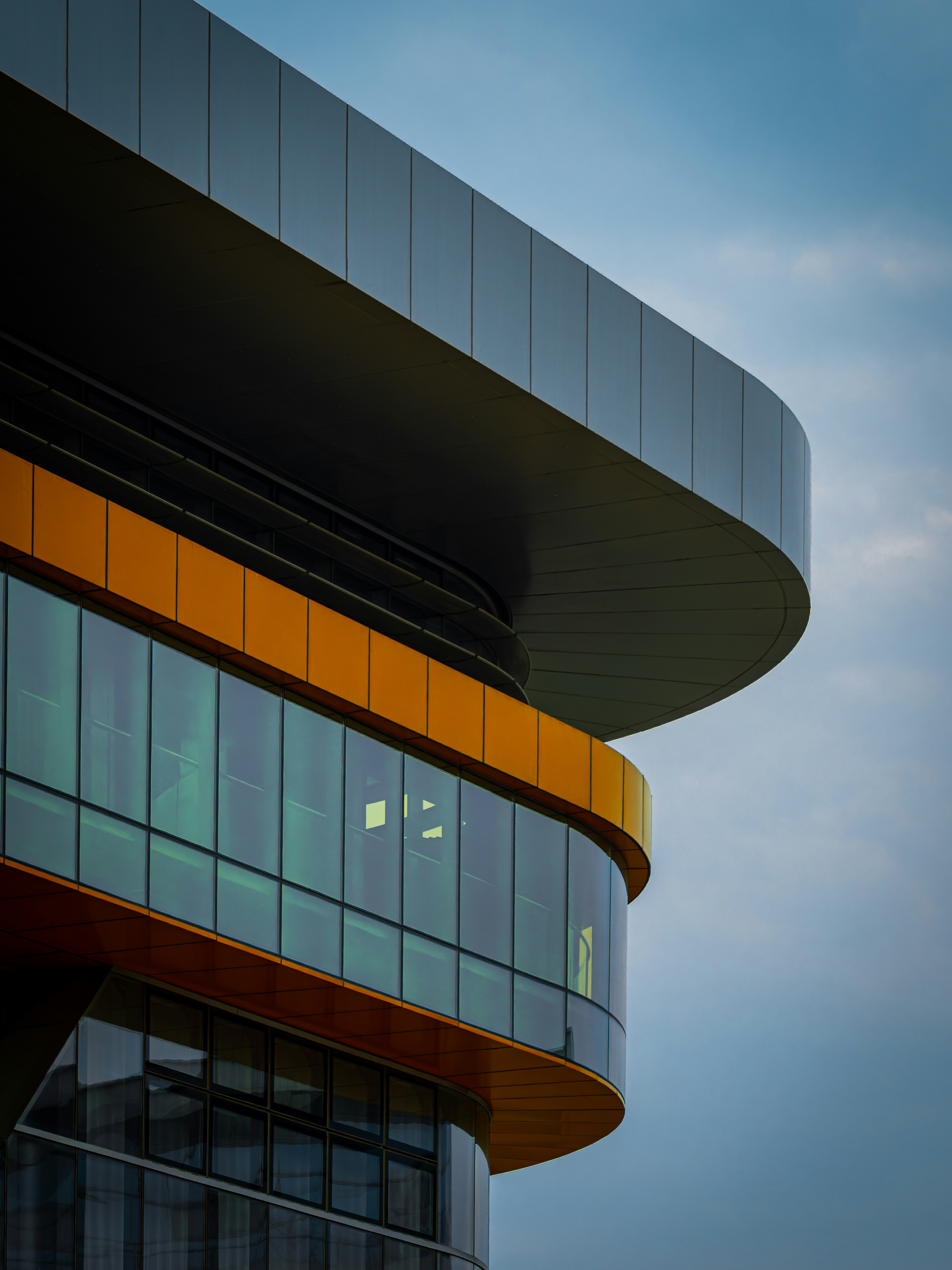 Curved Glass Capsule: A Modern Facade in Orange Lines