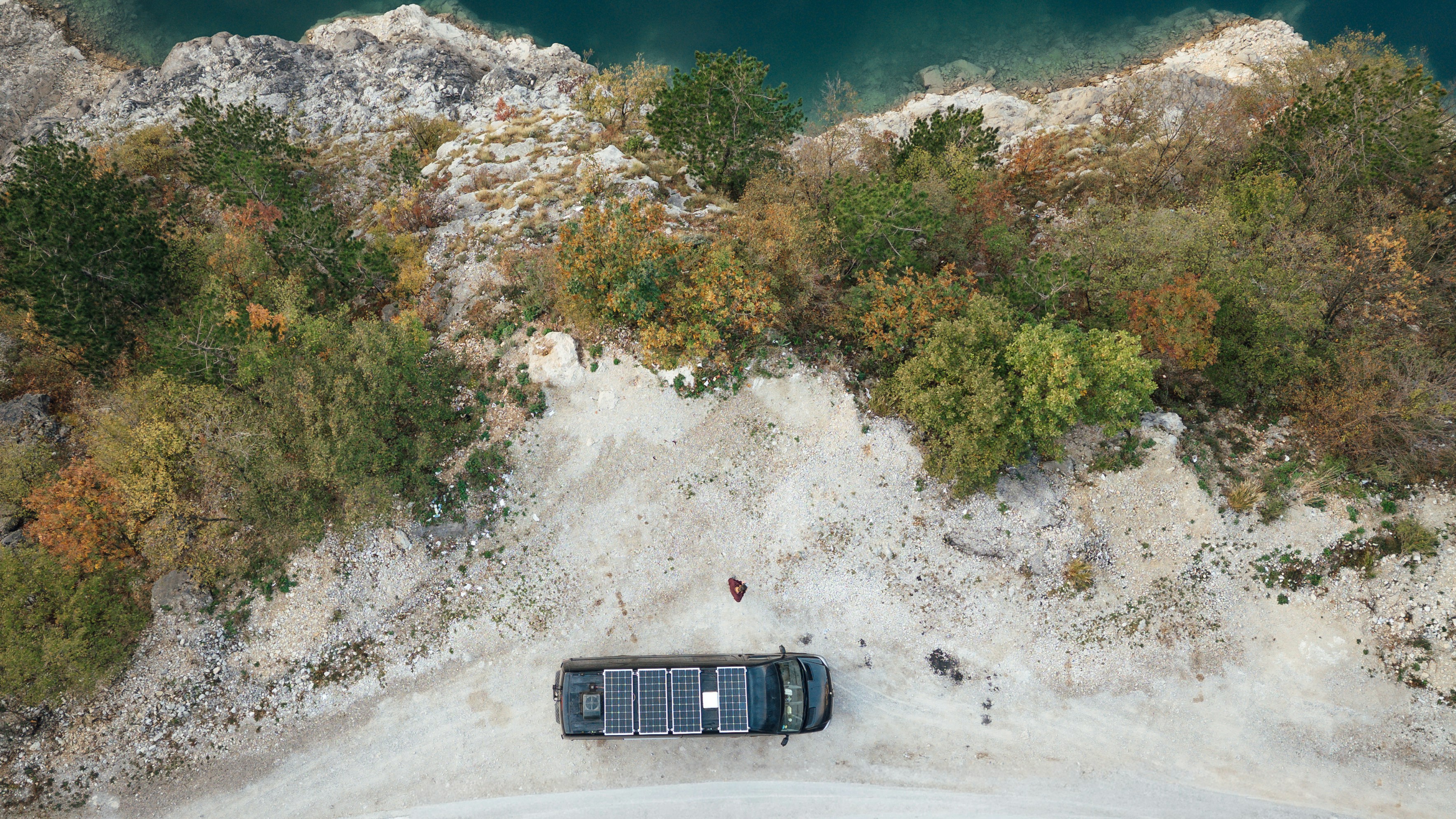 Rugged Coastal Shoreline Drop: A Truck Resting Beside Pine and Autumn Trees