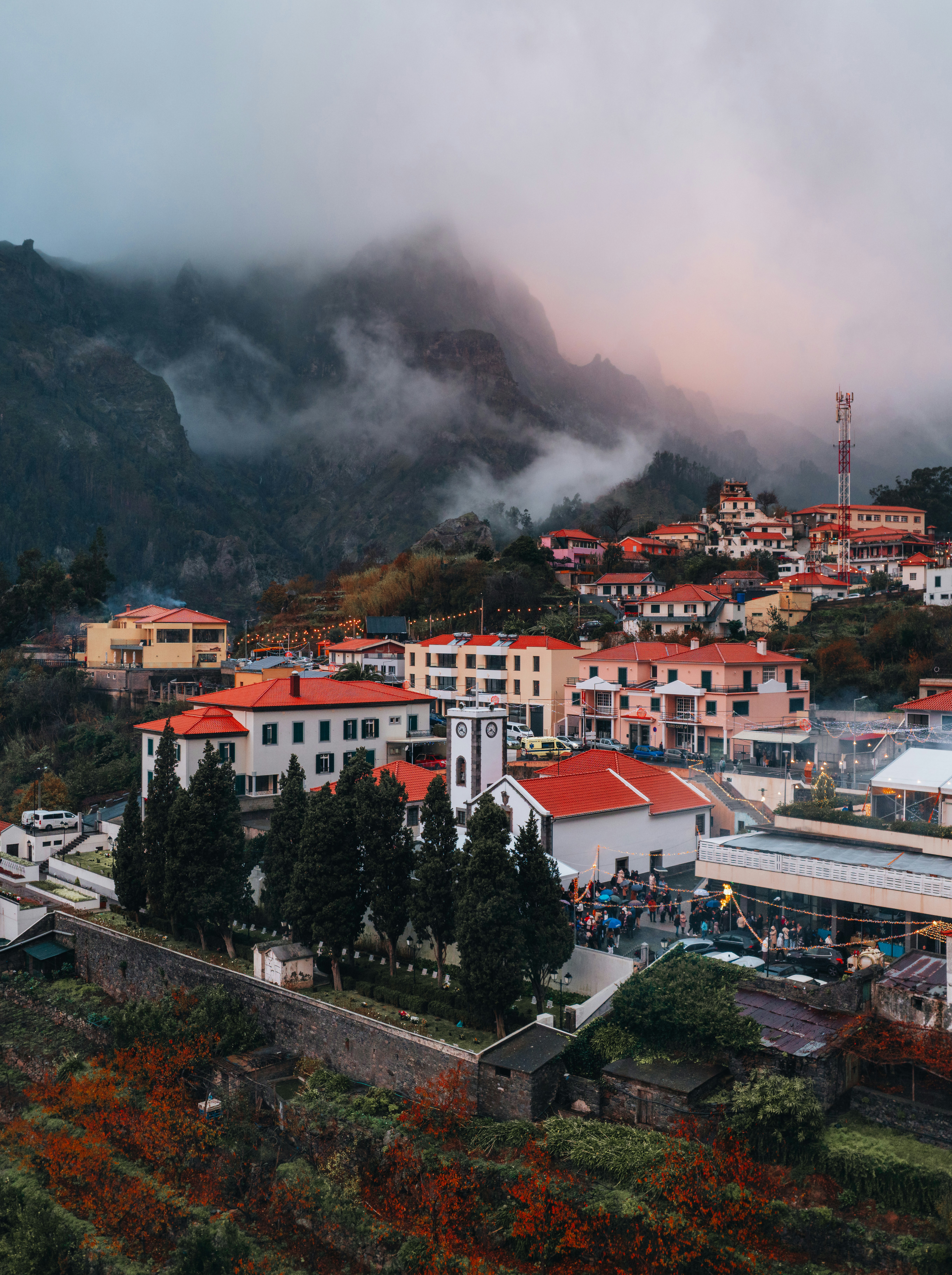 Terraced village beneath a misty alpine ridge at dusk