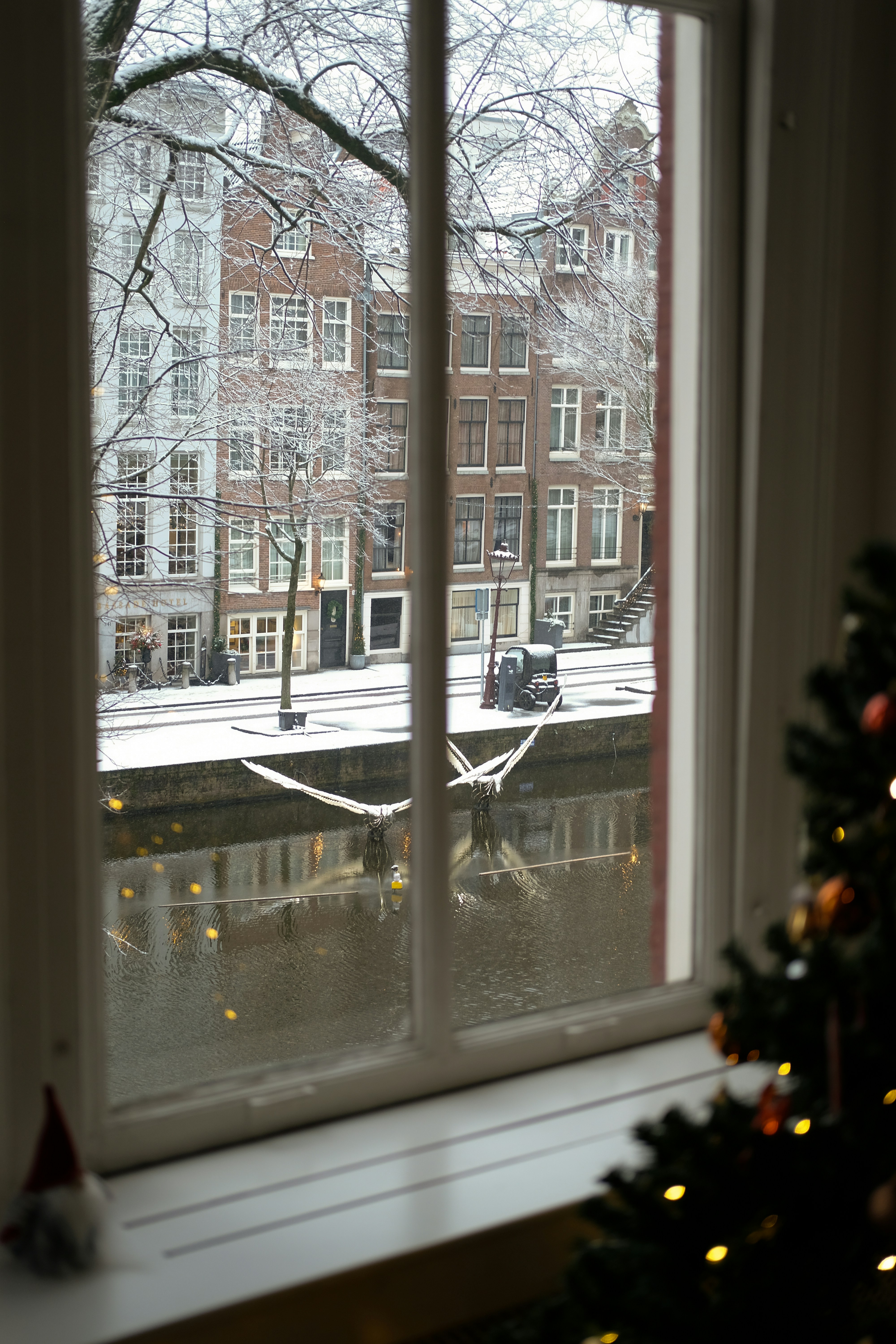 Snowy canal view through a window with a frosted cityscape
