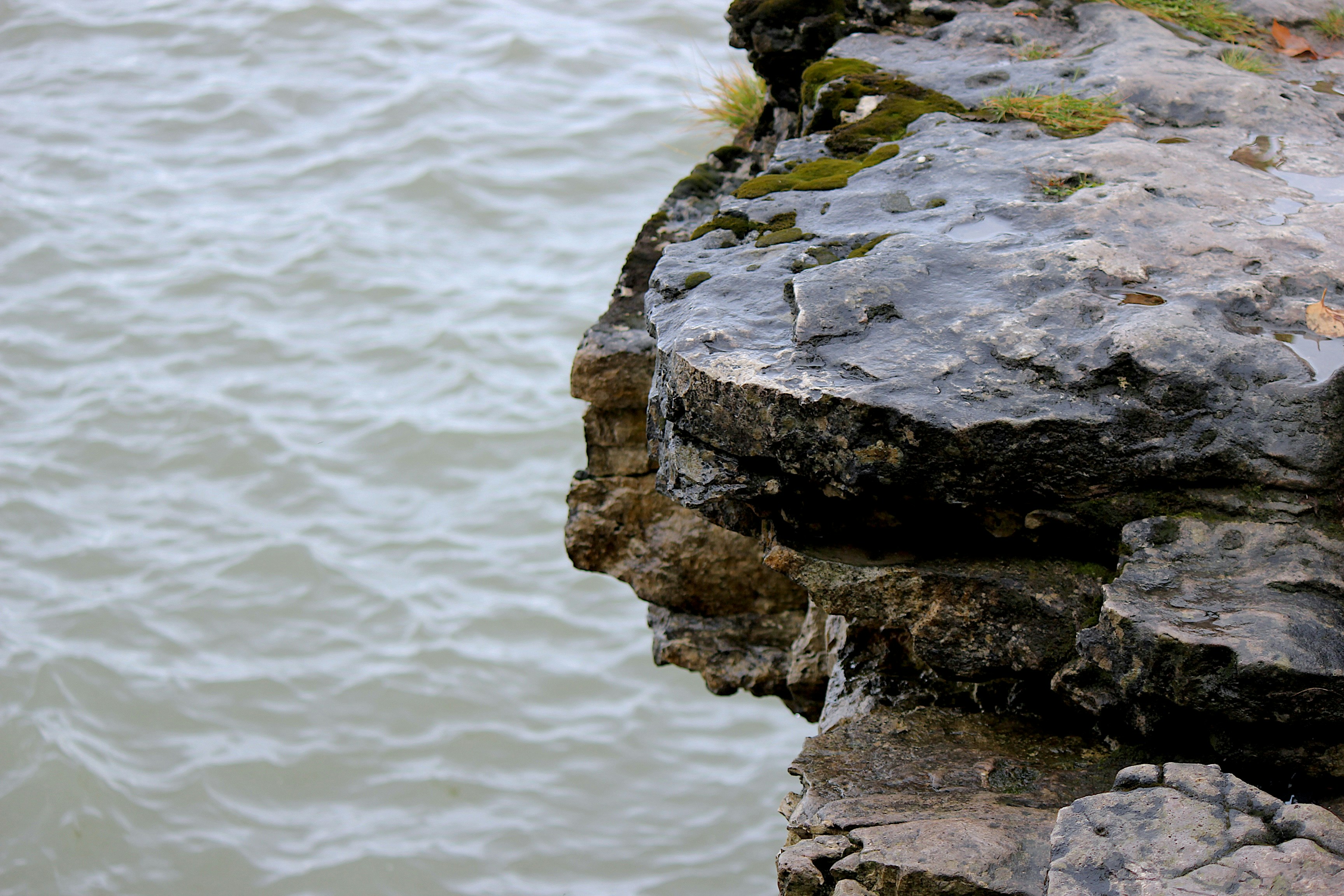 Edge of Stone: Weathered Cliff Over Calm Water