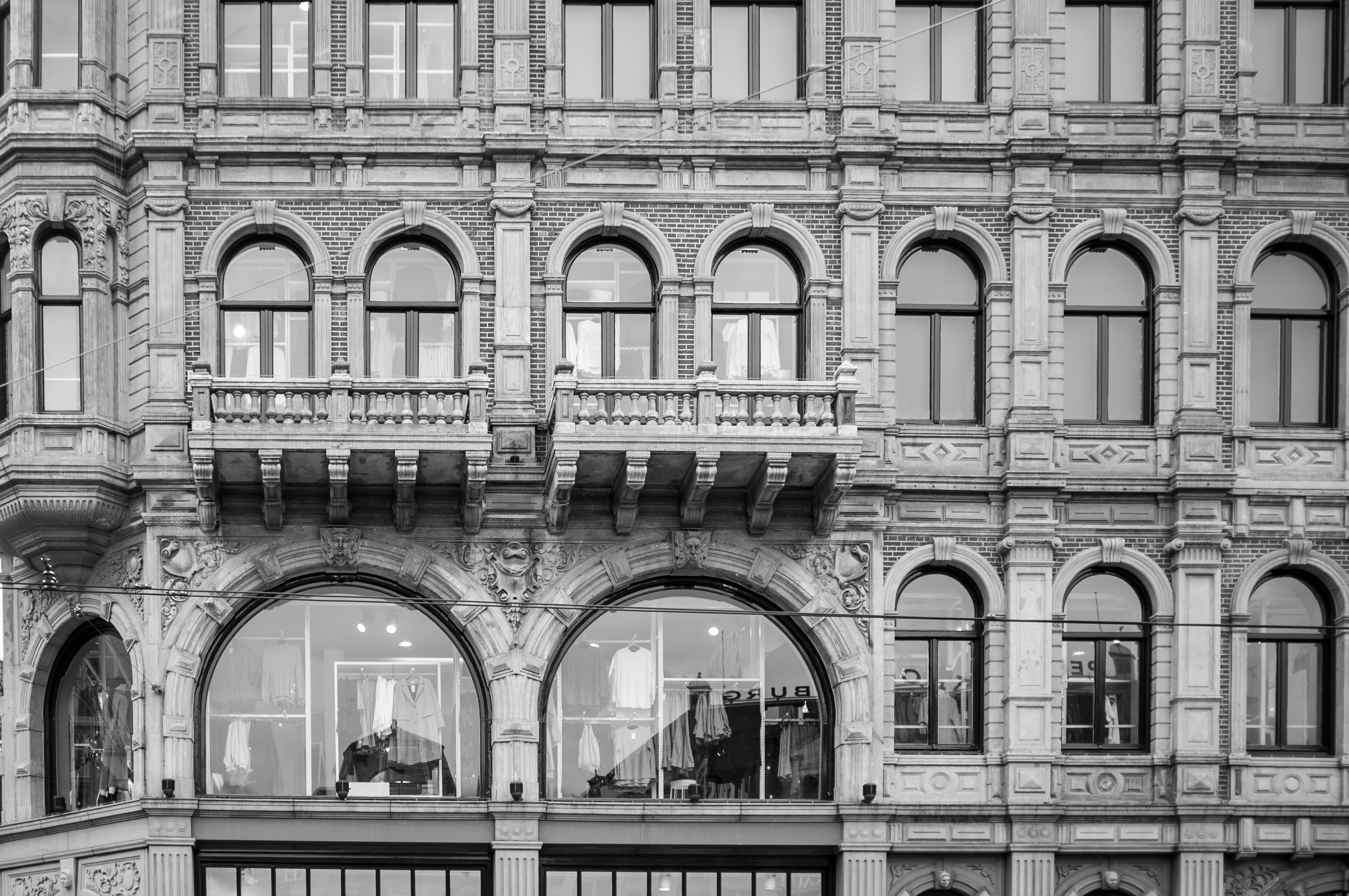 Ornate Facade Frames: Arched Windows Beneath Carved Cornices