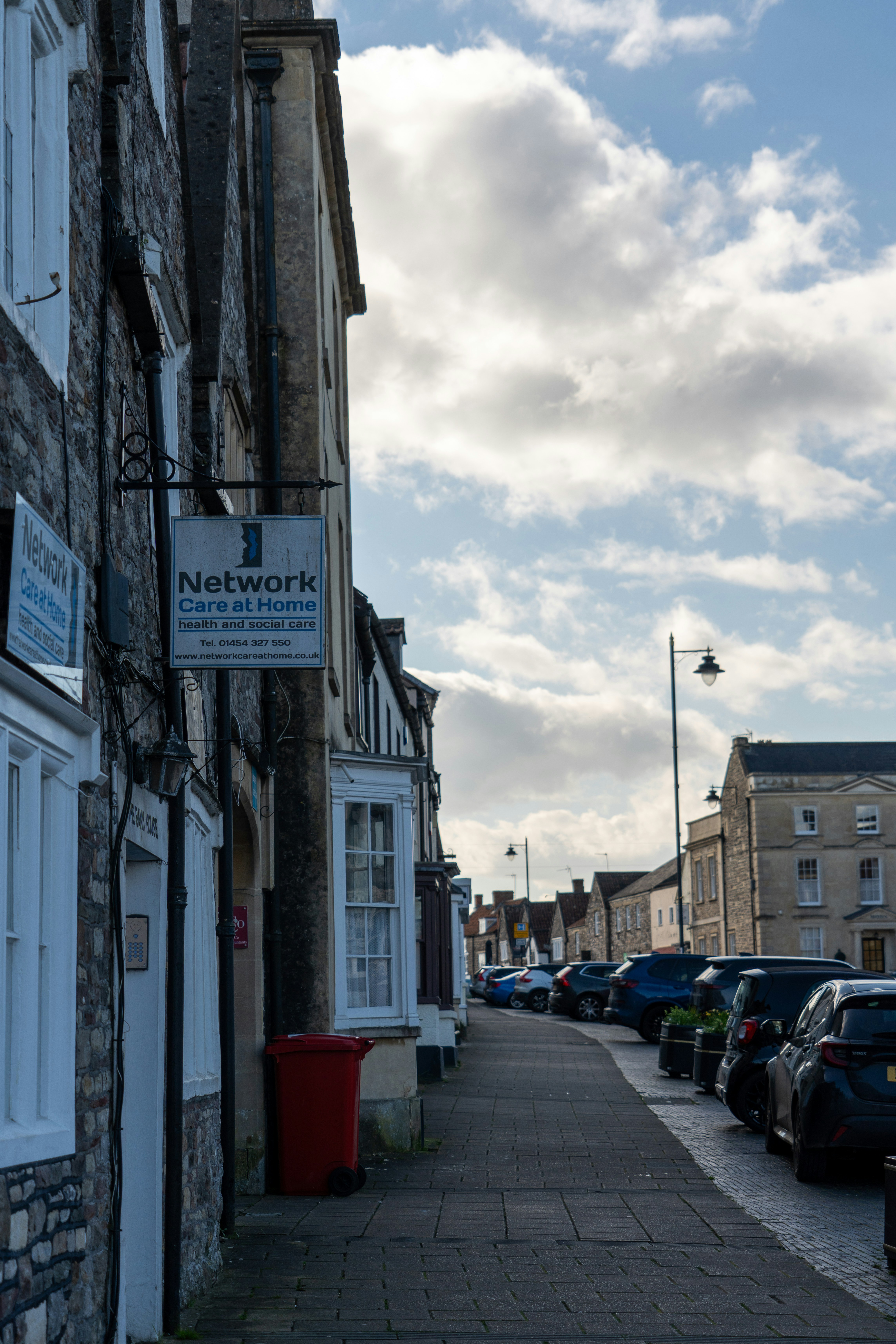 Cobbled Street Corridor: Signs, Cars, and Cloudy Sky