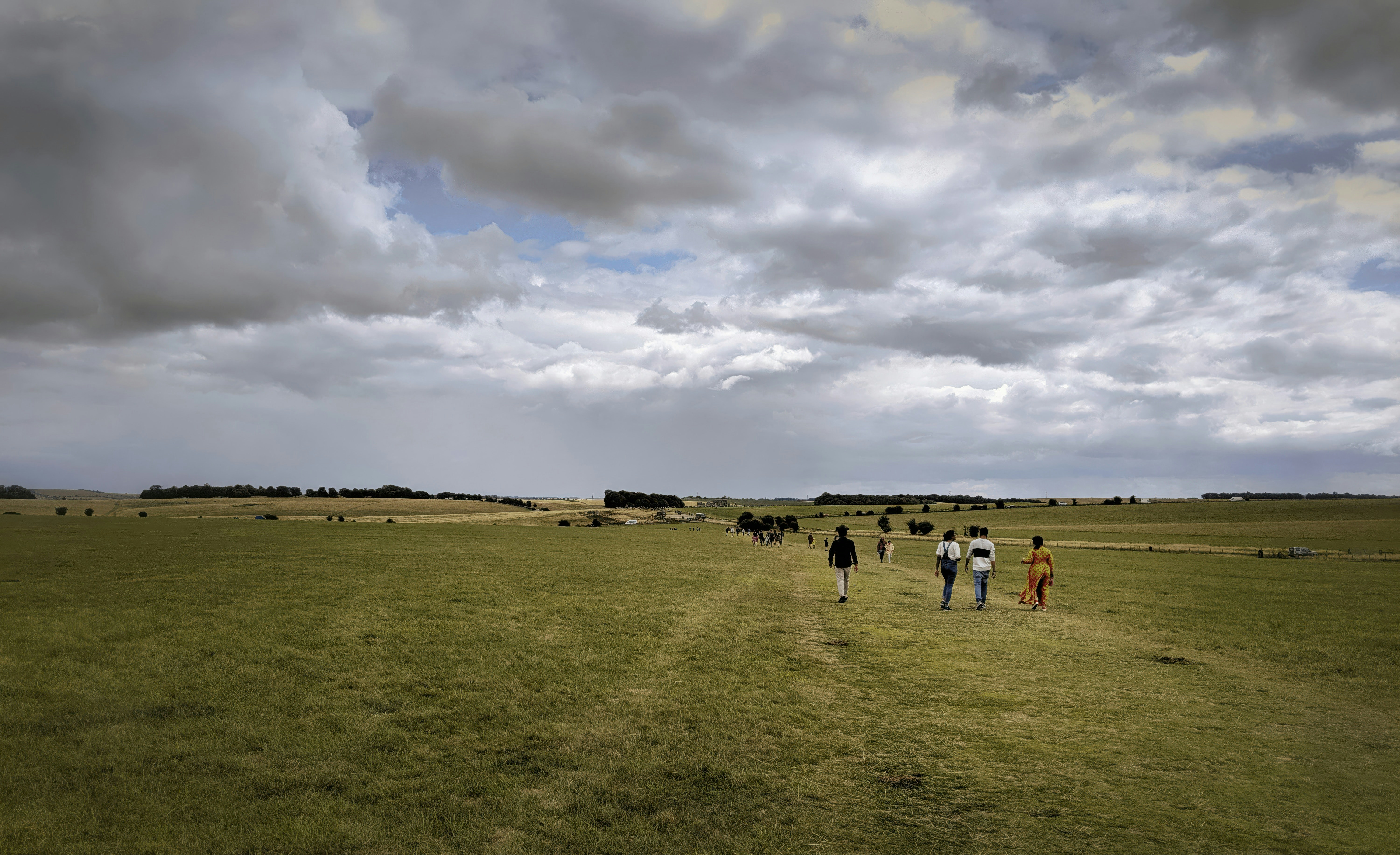 Trail of Wanderers Across Open Prairie Under Rolling Clouds