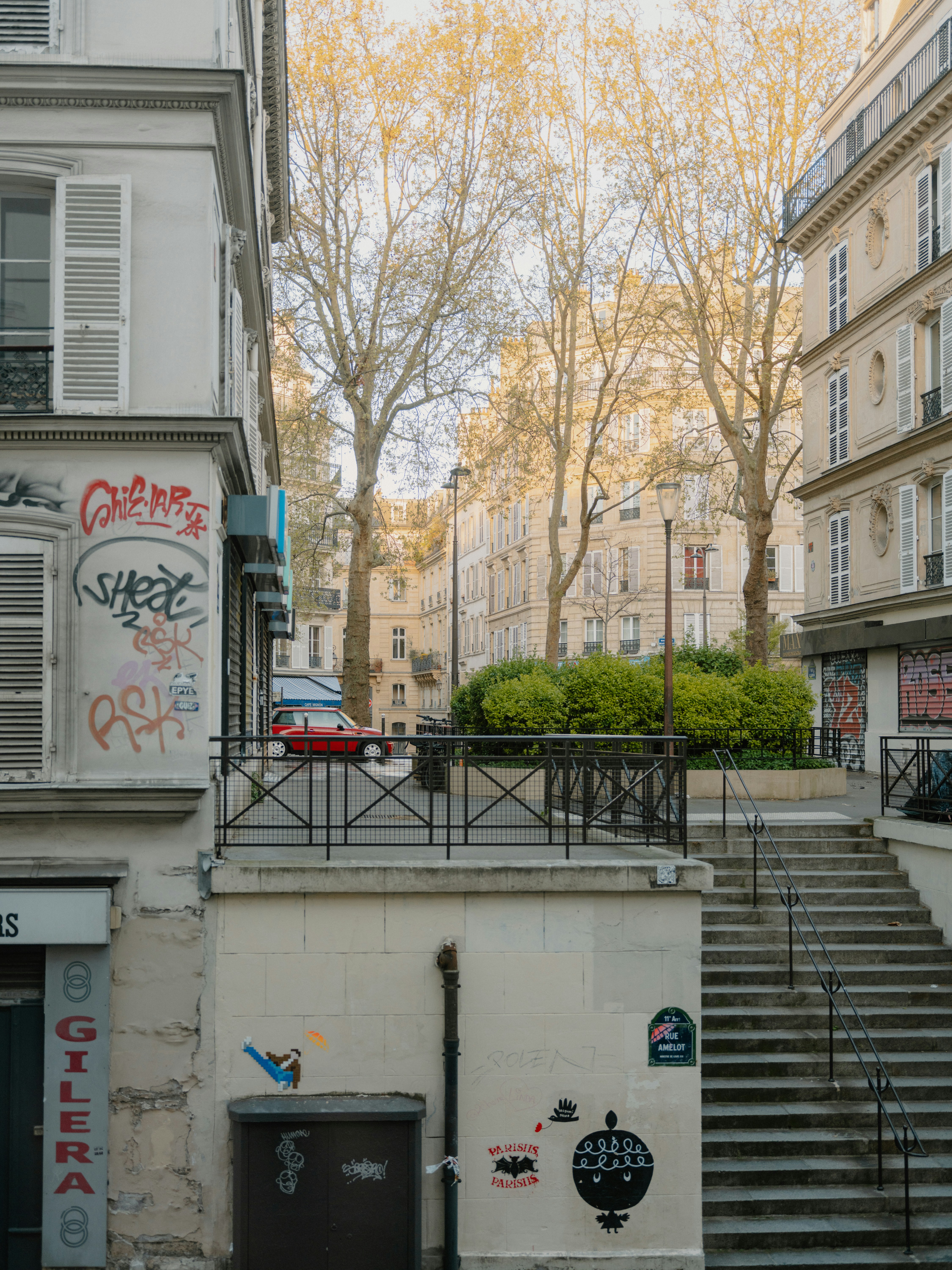 Sunlit Parisian Side Street with Graffiti and Staircase