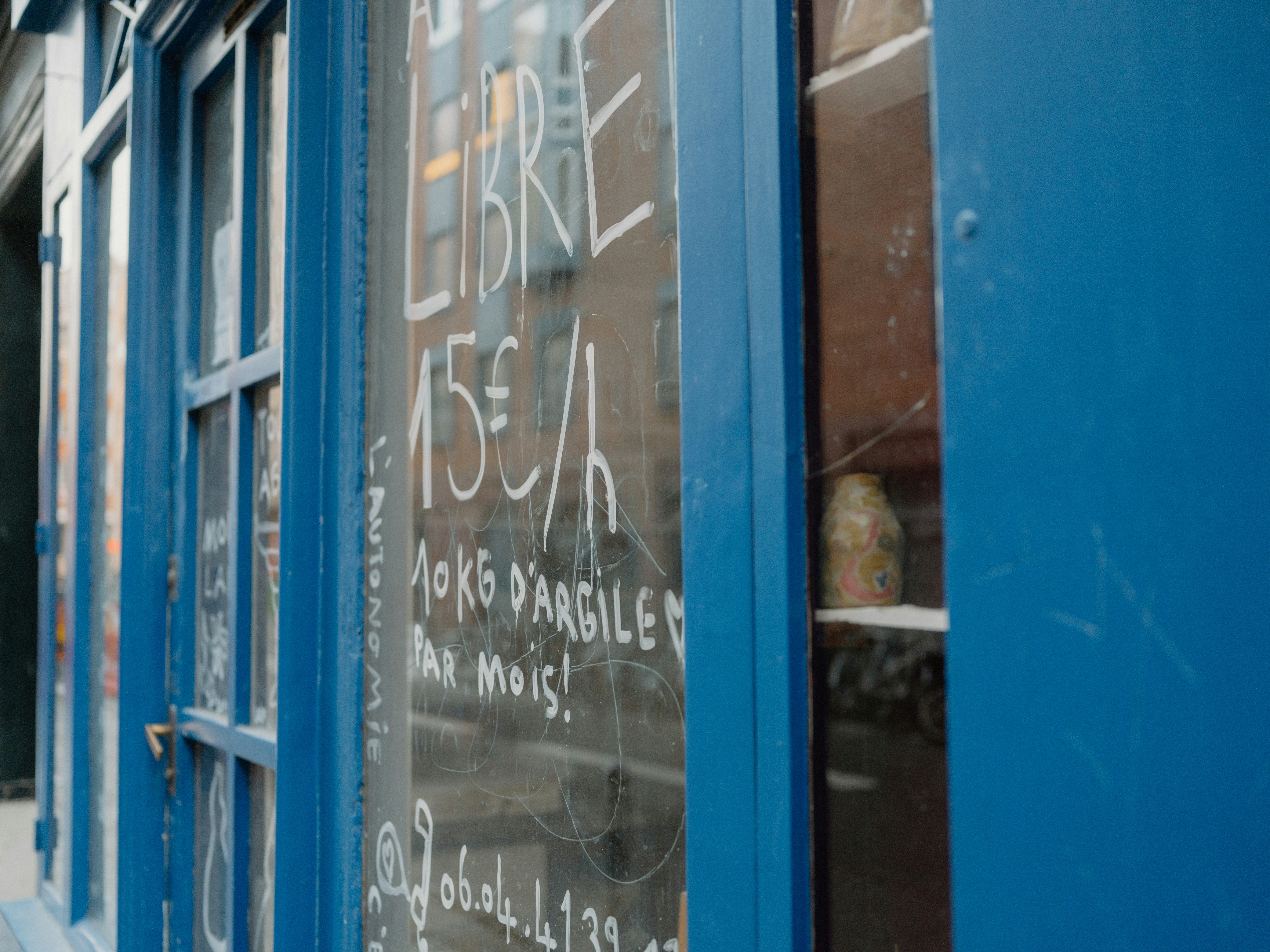 Blue storefronts and chalked windows along a narrow city street