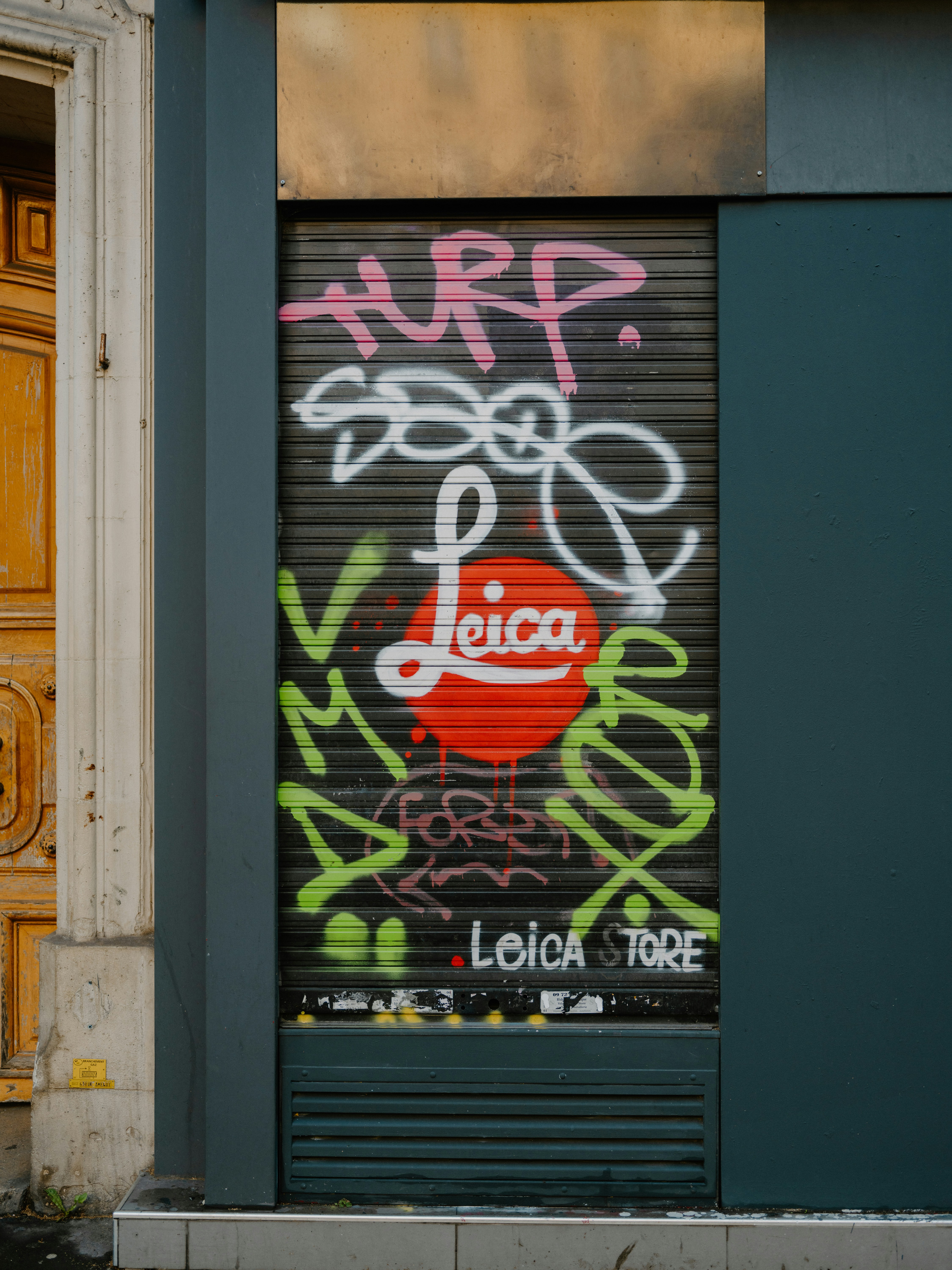 Graffiti covers a closed store shutter with leica logo.