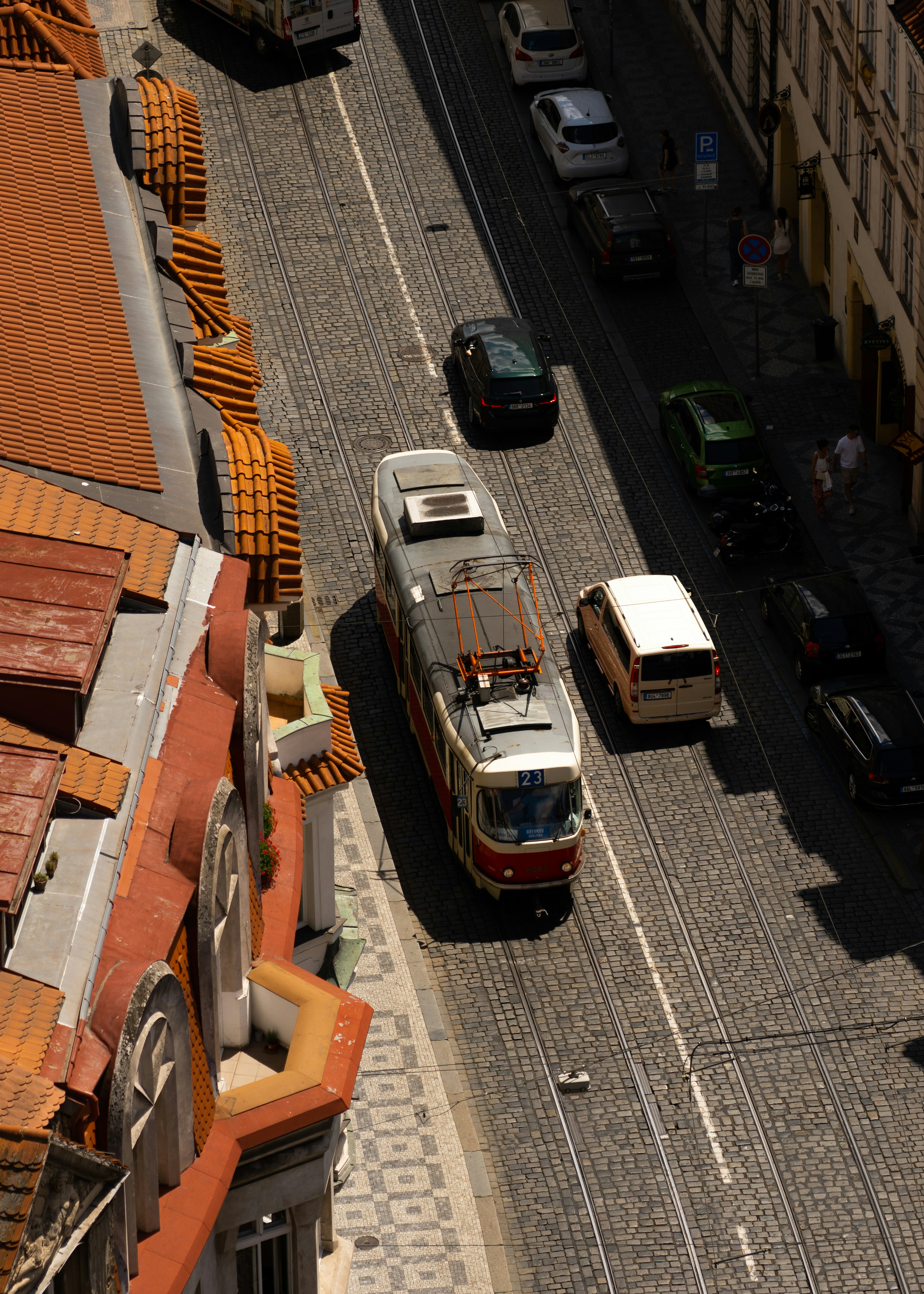 Aerial streetcar procession along sunlit cobblestones