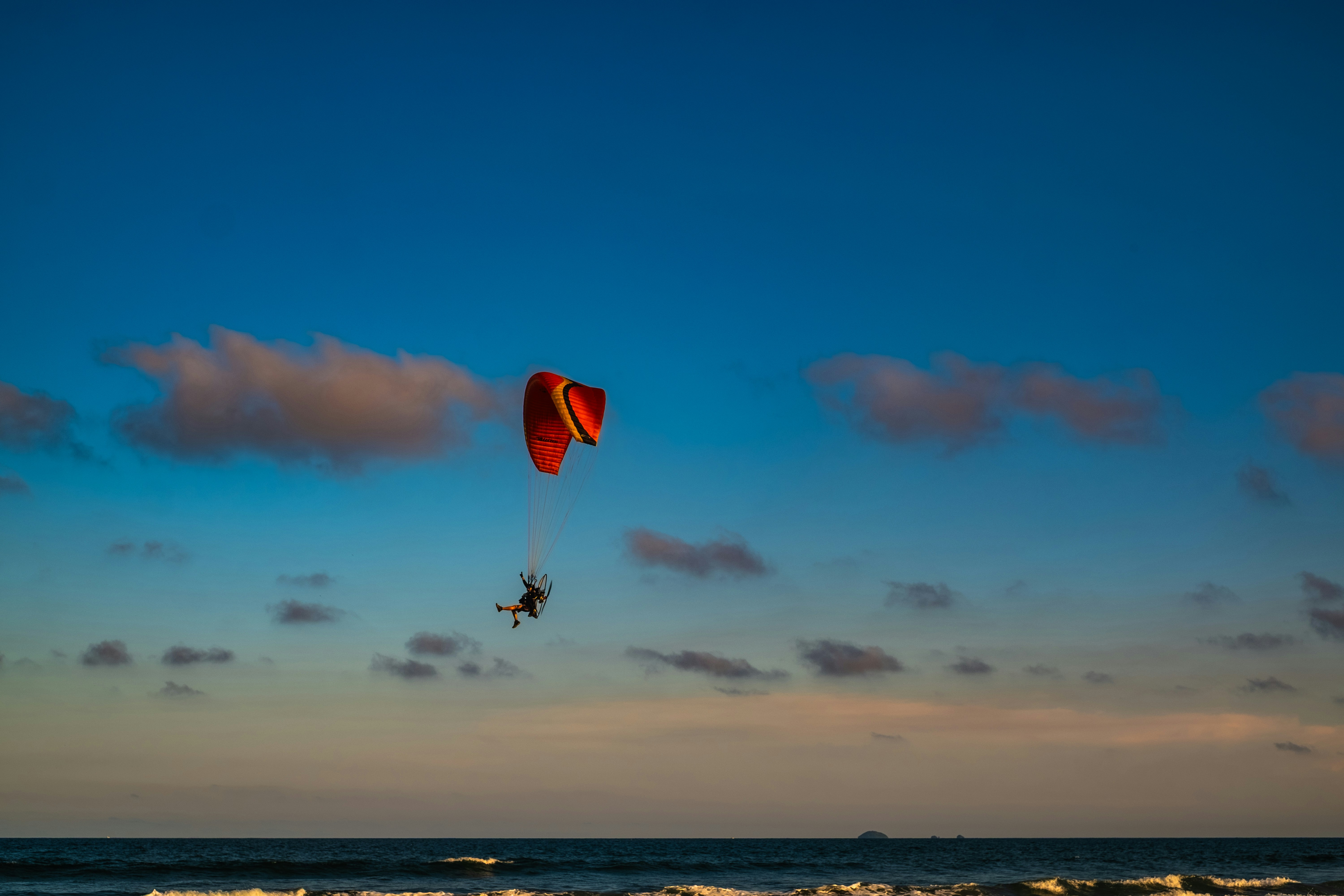Distant Descent: Paraglider Against a Sea-Blue Horizon