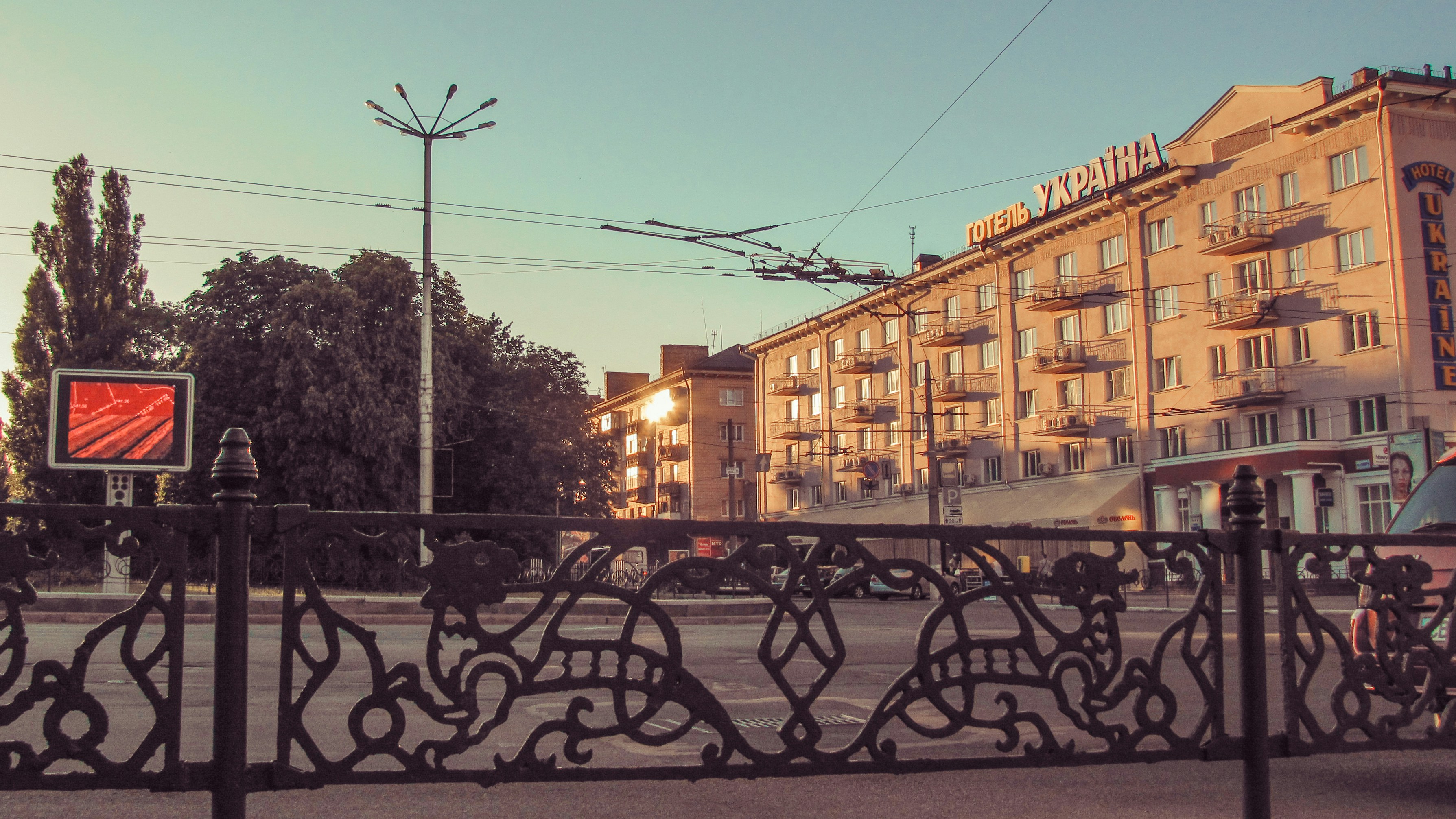 City Gatekeeper: Ornate Fence Framing a Sunlit Boulevard