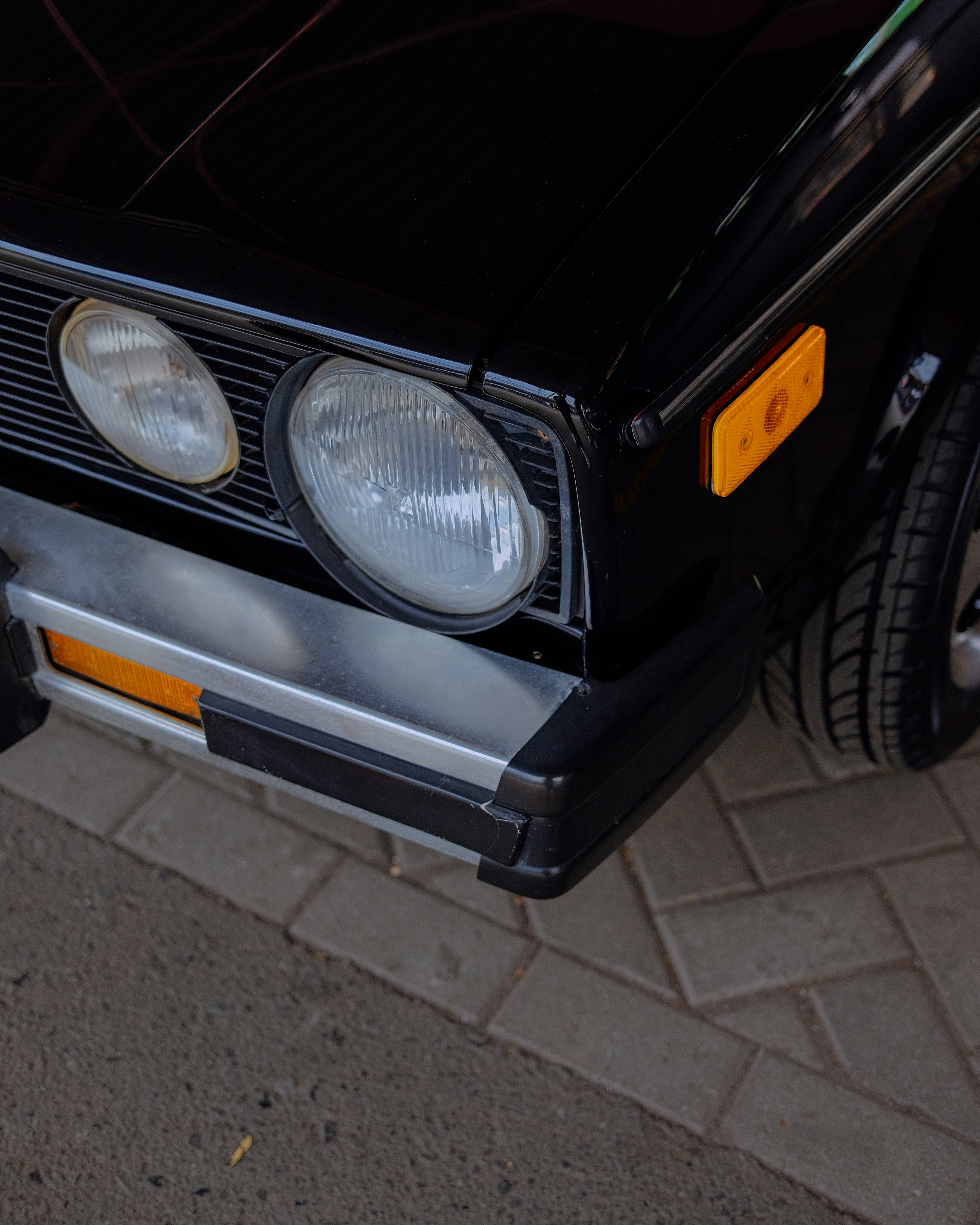 Tail-light Teardrop: A Vintage Car’s Front Corner in Shadowed Quiet