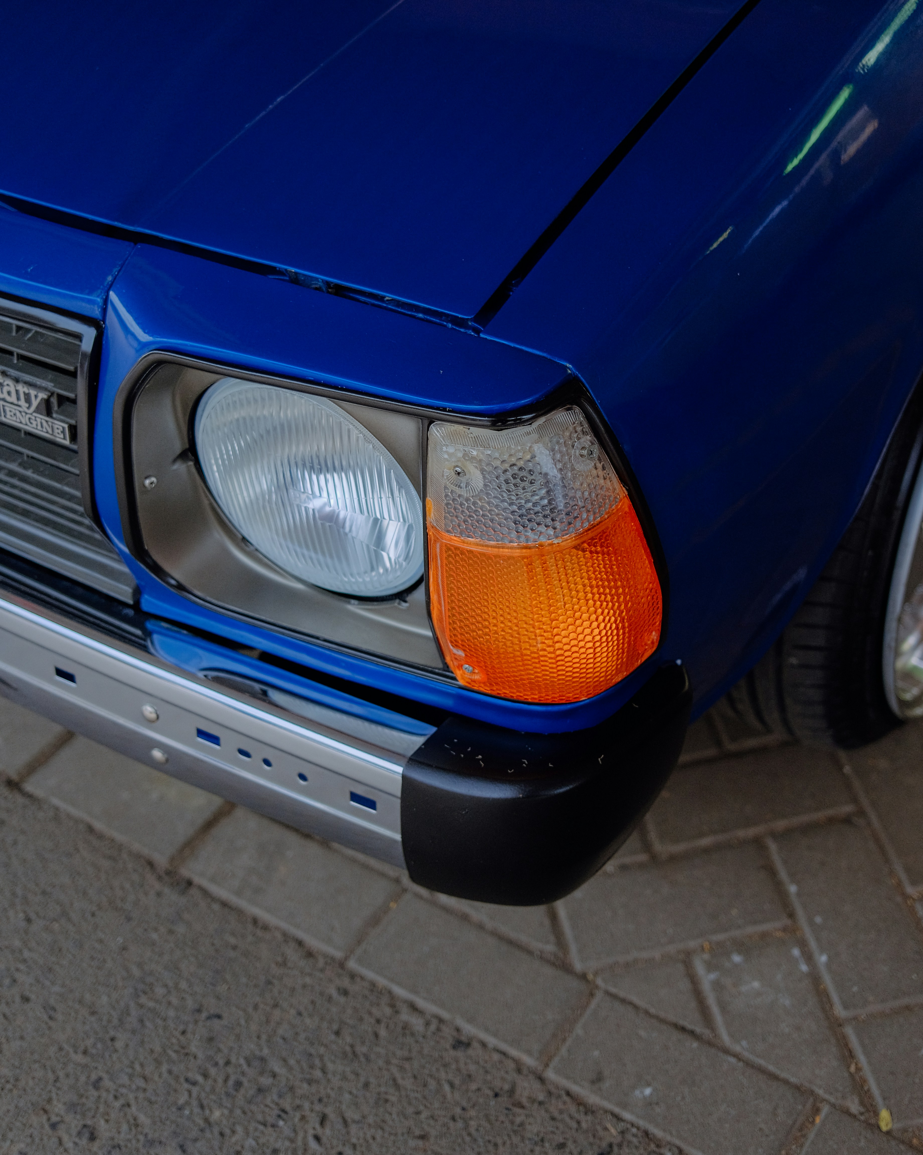 Blue coupe corner: close-up of headlight and orange signal on a vintage car
