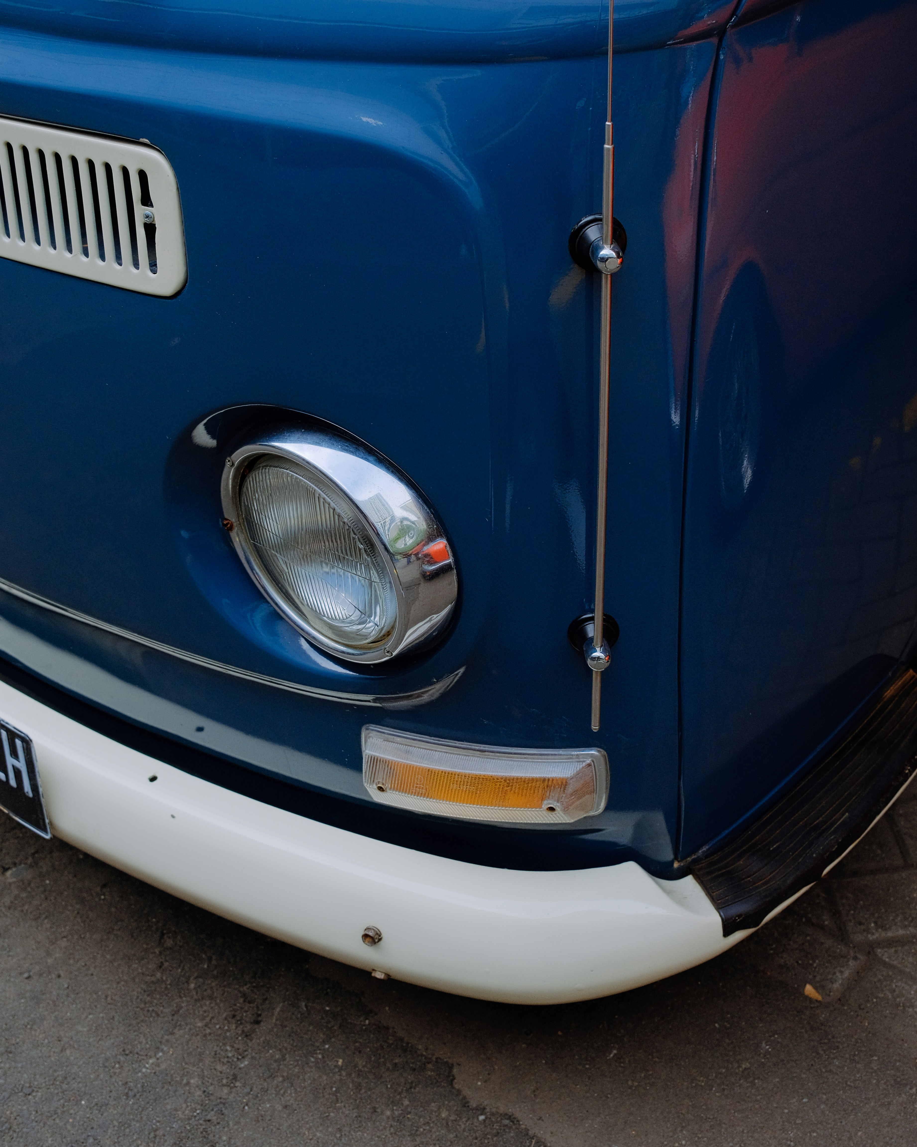 Nostalgic blue front: a vintage bus cab with chrome headlamp and white bumper