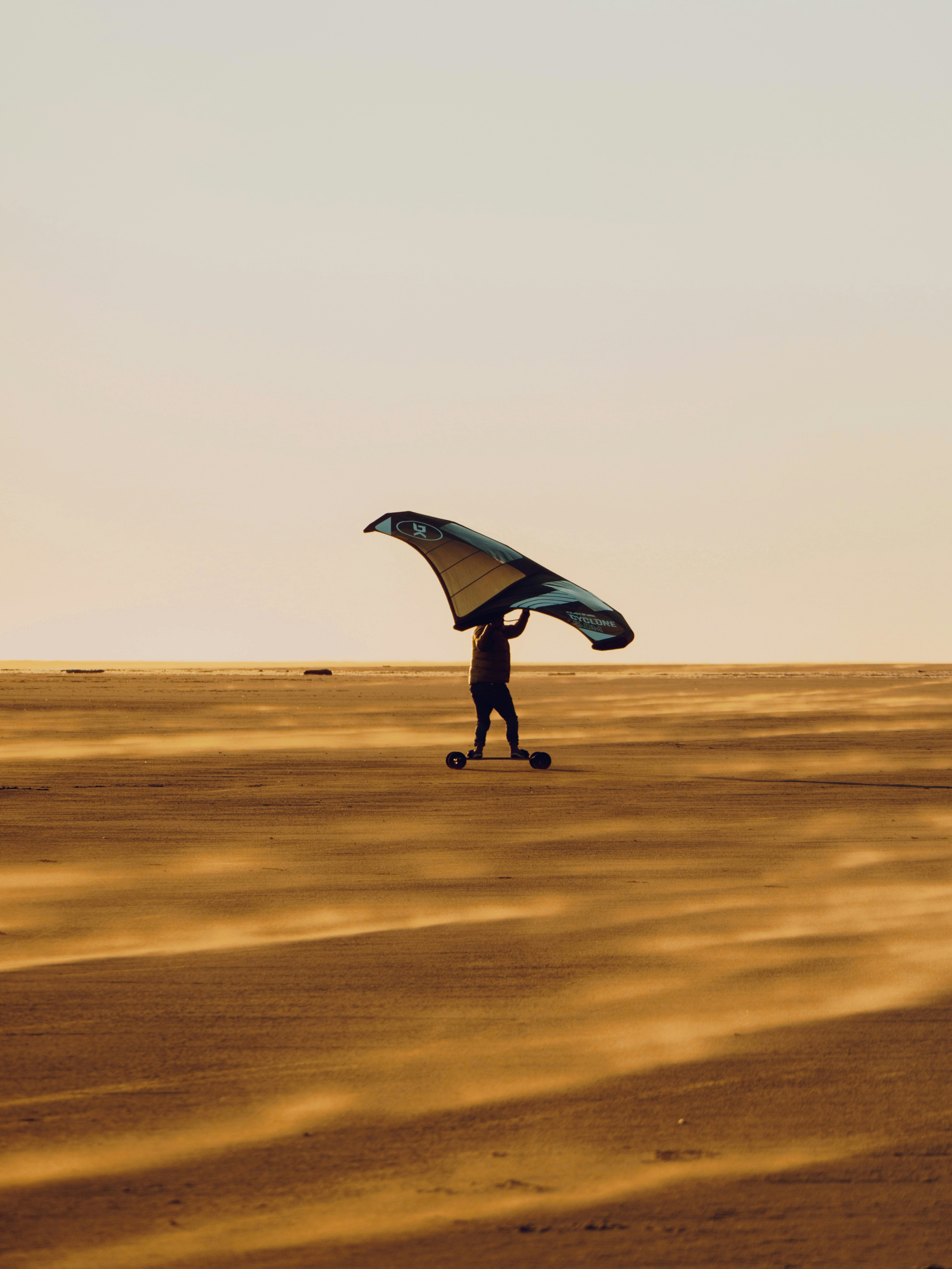 Winged at the Edge: A Kiteboarder Carries a Surfboard Across Dune Skies