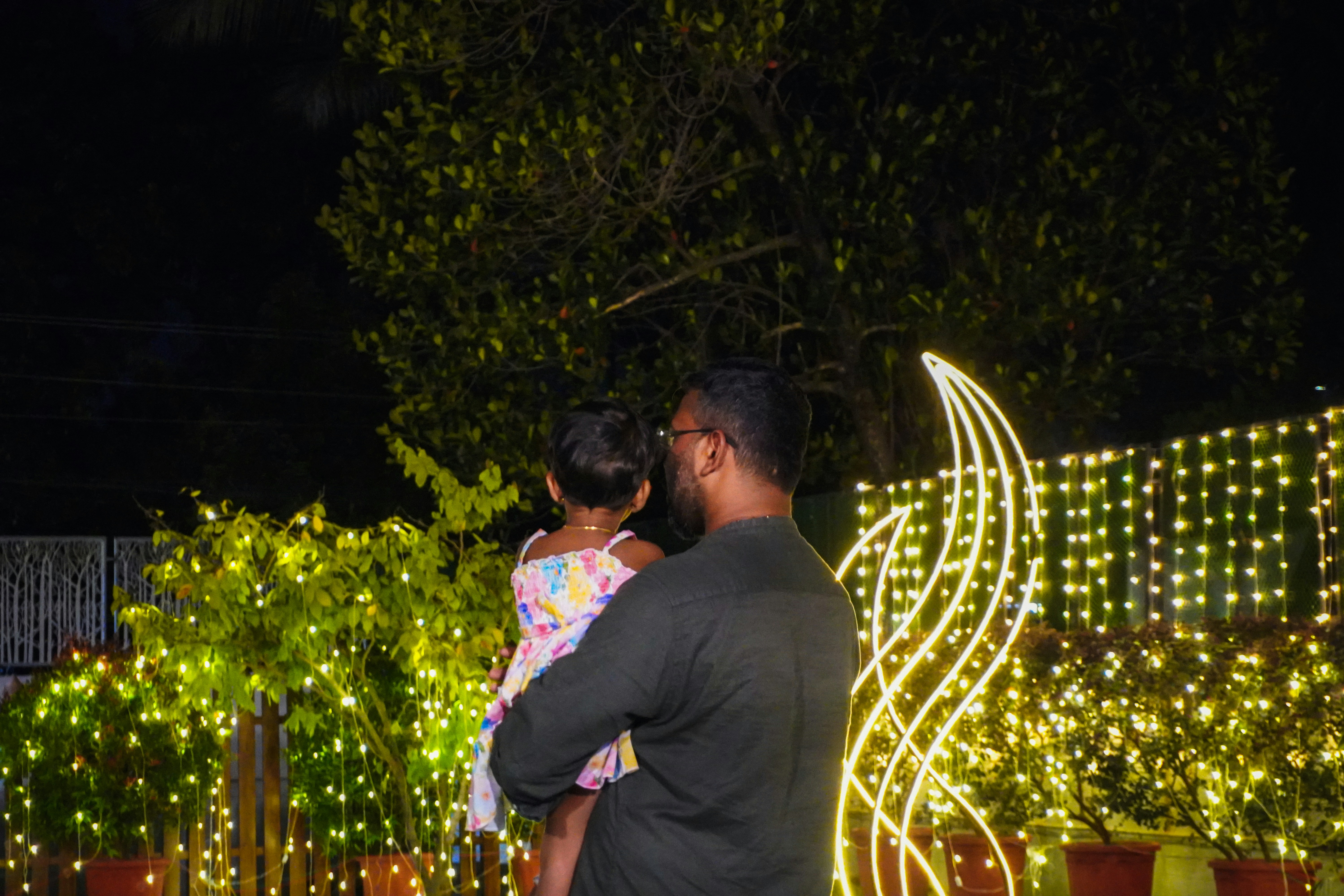 Night Orchard: Father and Child Beneath Golden Lights