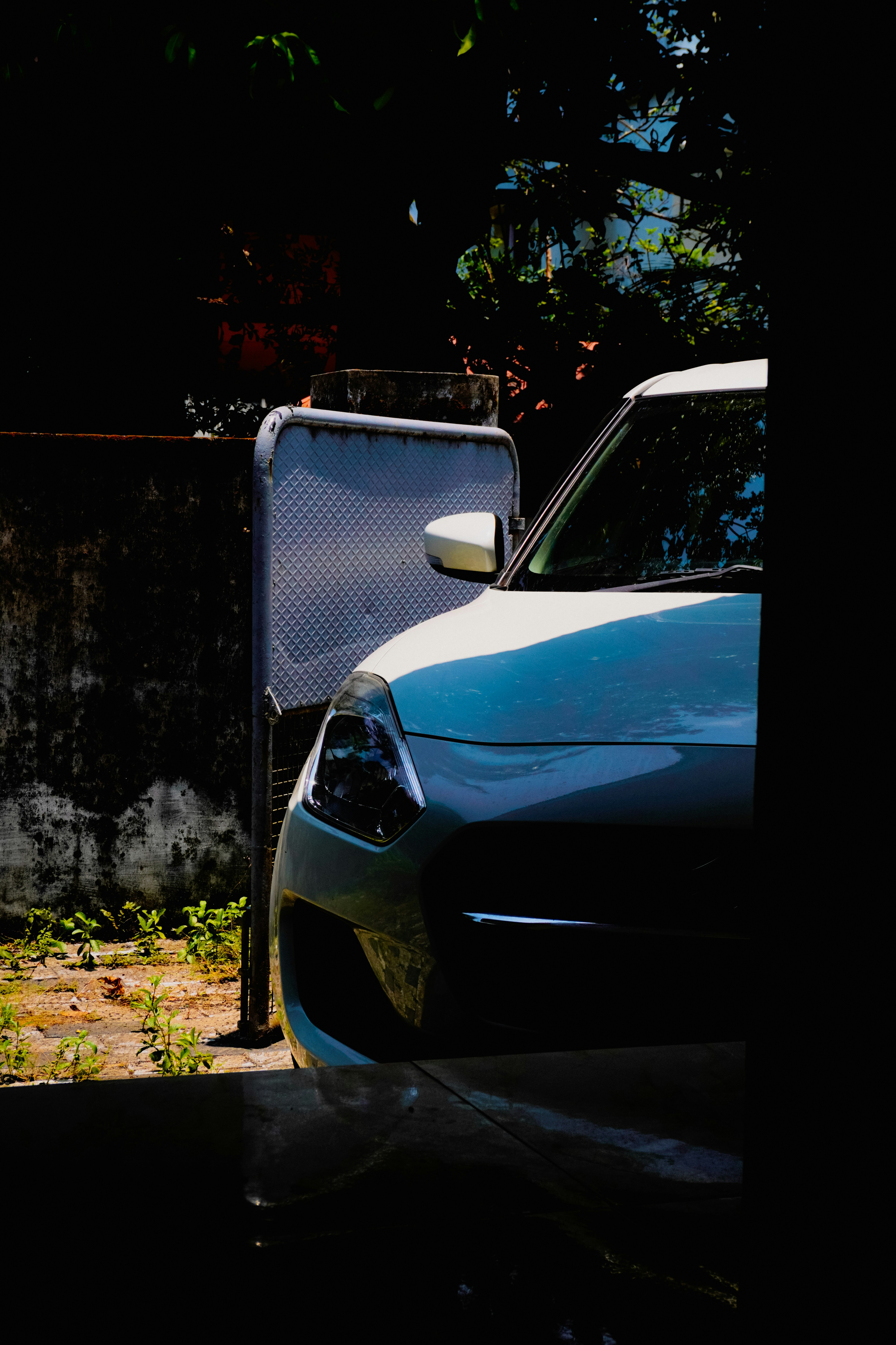 Blue Car Emerges from a Shadowed Frame